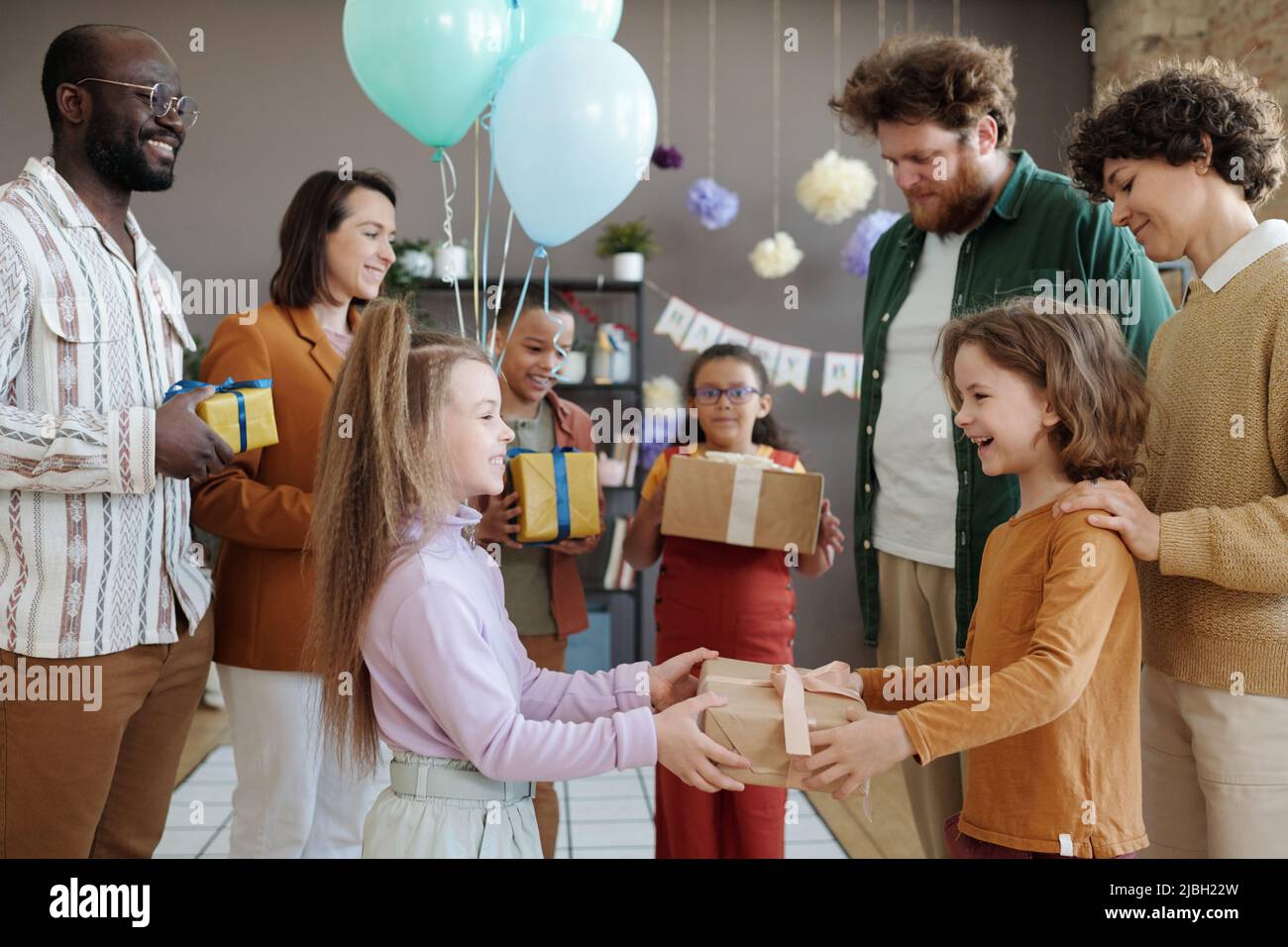 Cute little boy happy to get present from his friend with his parents ...