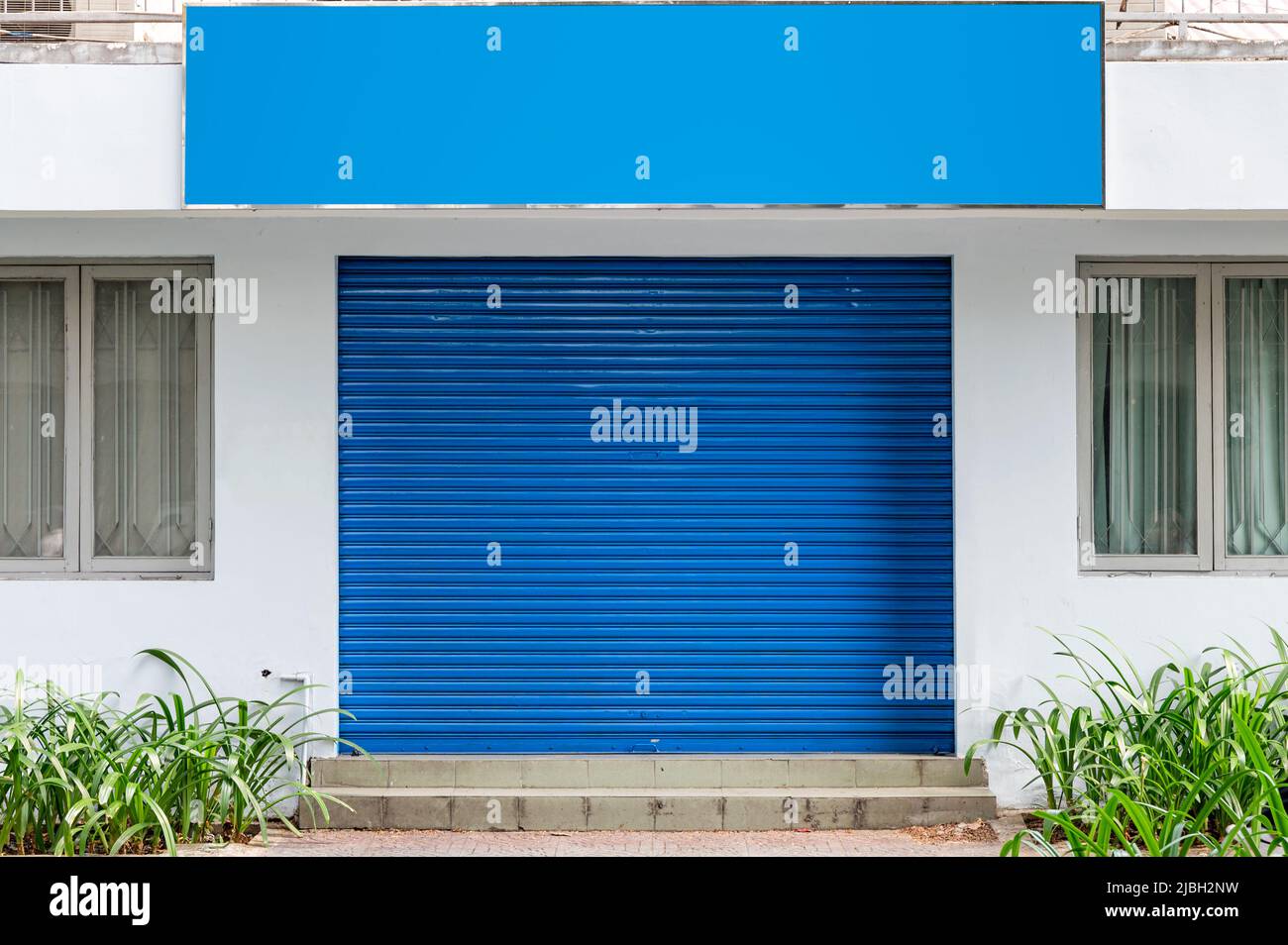 Exterior of closed blue shutter roller door with blank billboard of ...