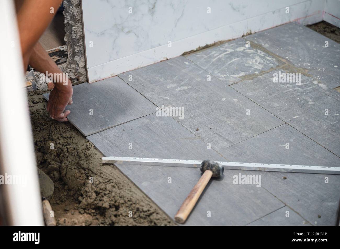 Contractor working with granite tile flooring with cement and tools in ...