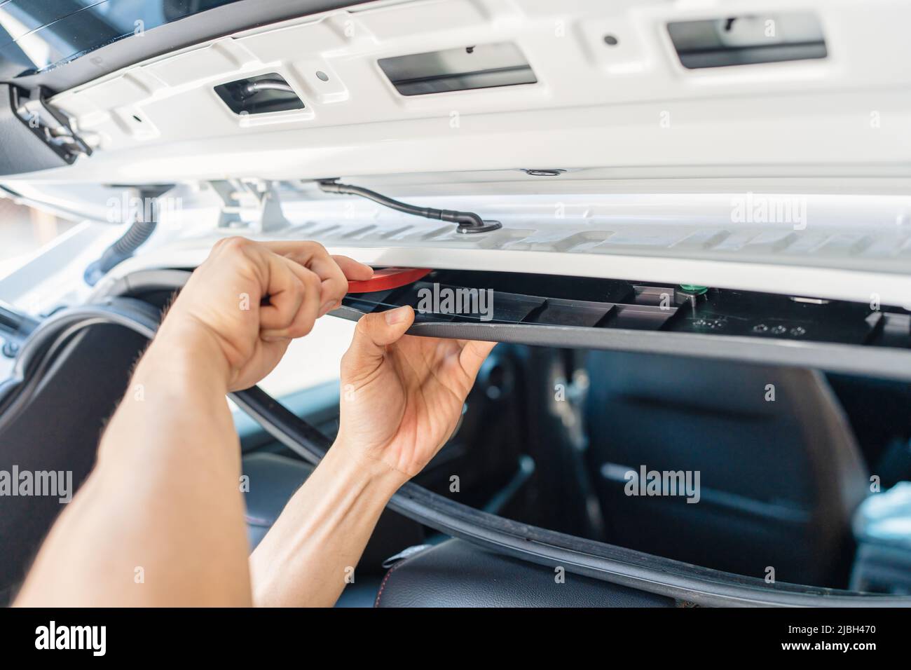 Hand of mechanic using wedge removing and installing a dash cam inside ...