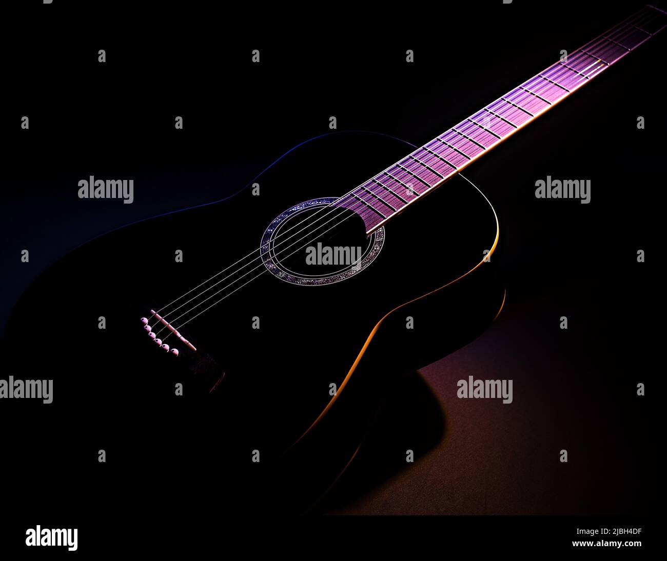 black guitar against split colored dark background. guitar music low ...