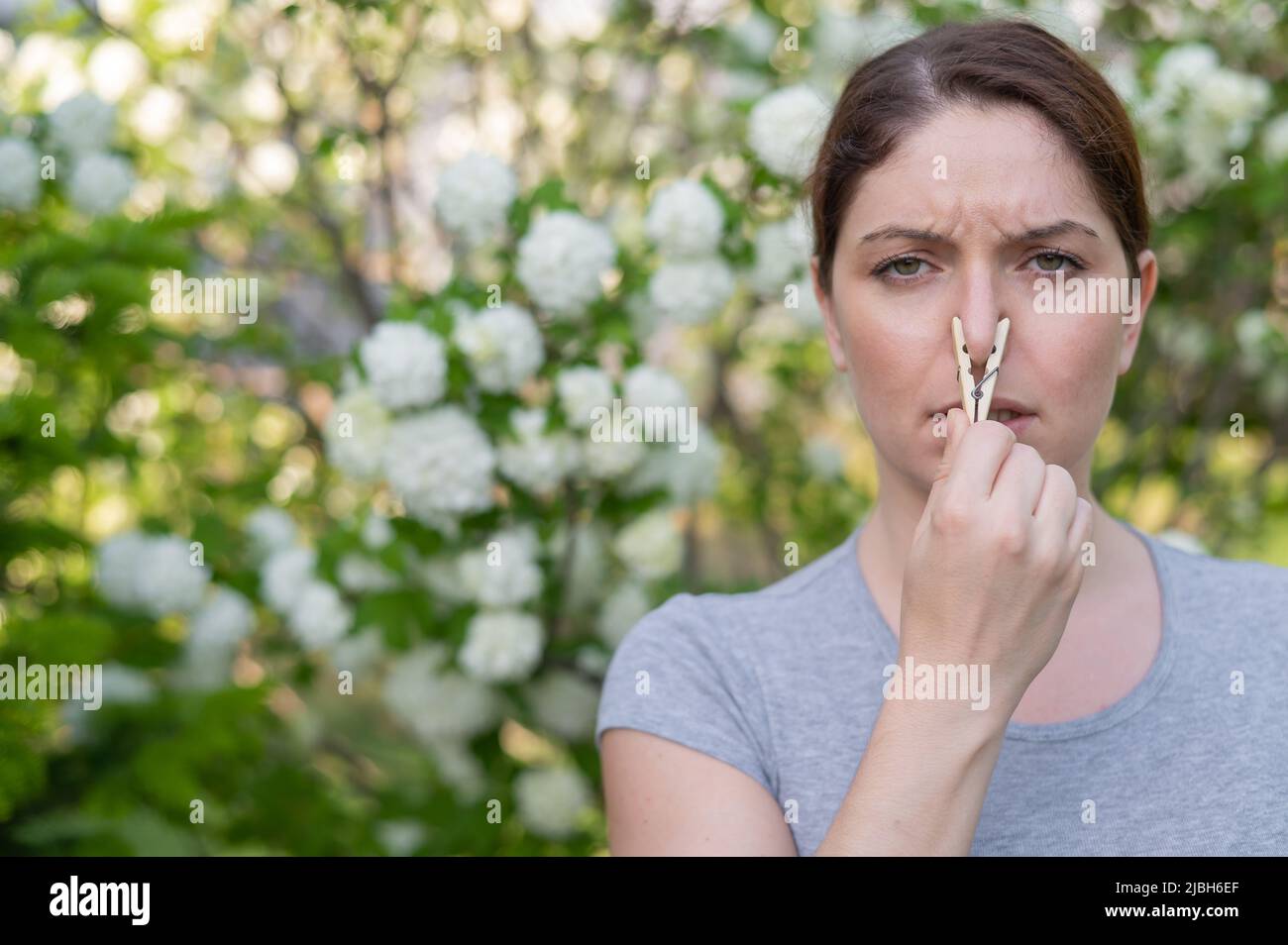 Caucasian woman with a clothespin on her nose on a walk in a blooming ...