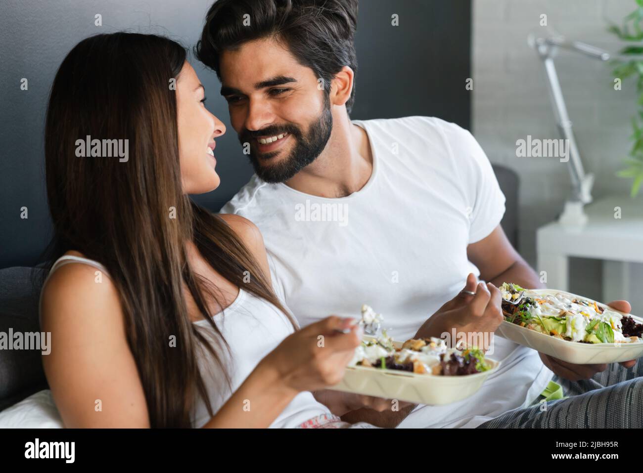 Healthy breakfast in bed. Young beautiful couple in love spending time ...