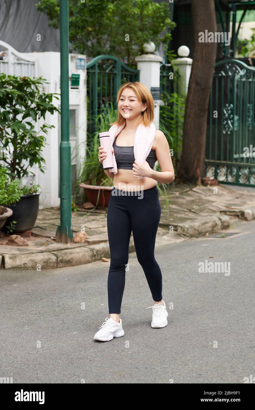Joyful young Asian woman walking home after morning jog Stock Photo - Alamy