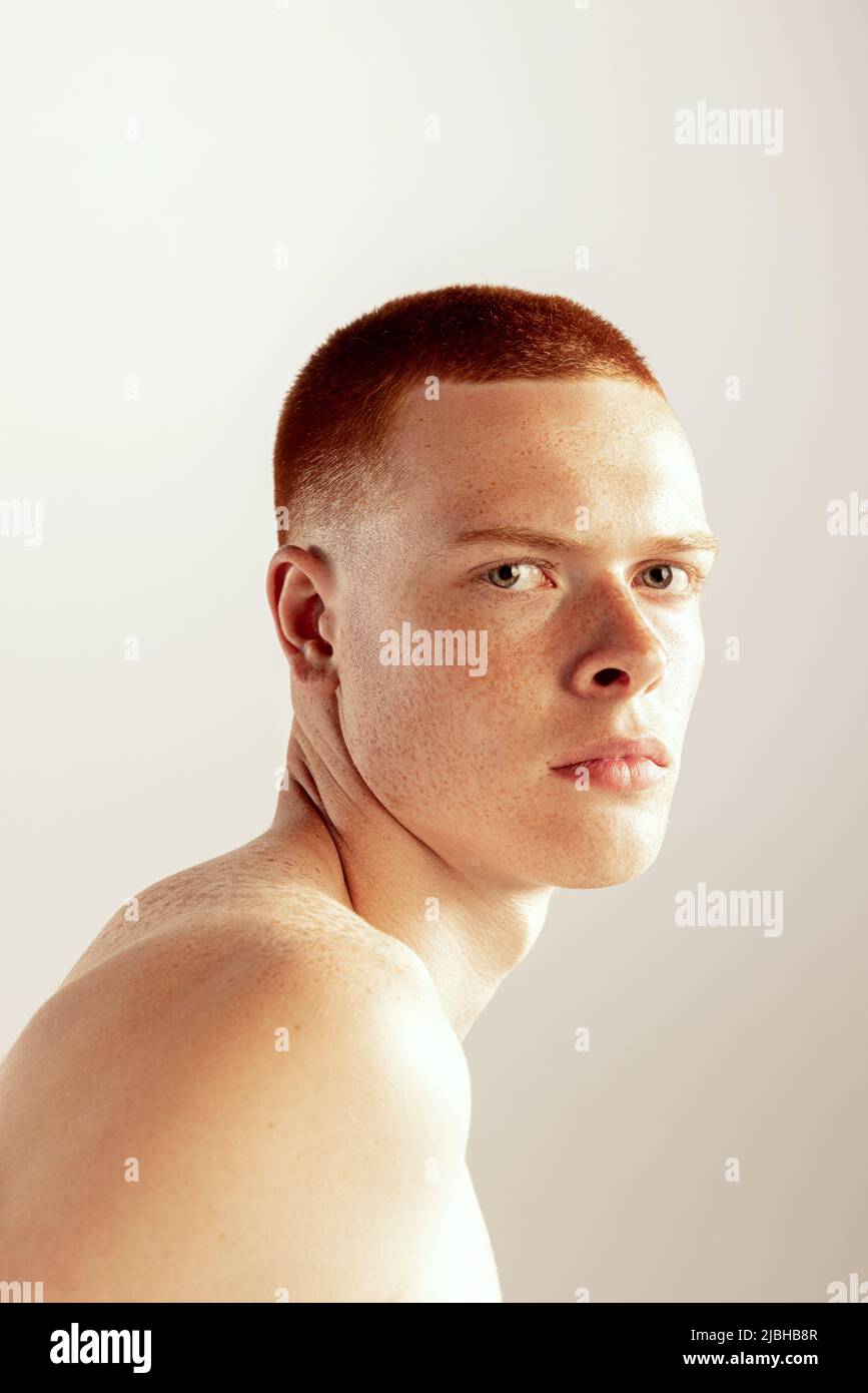 Portrait of young red-haired man with freckled face posing, seriously ...