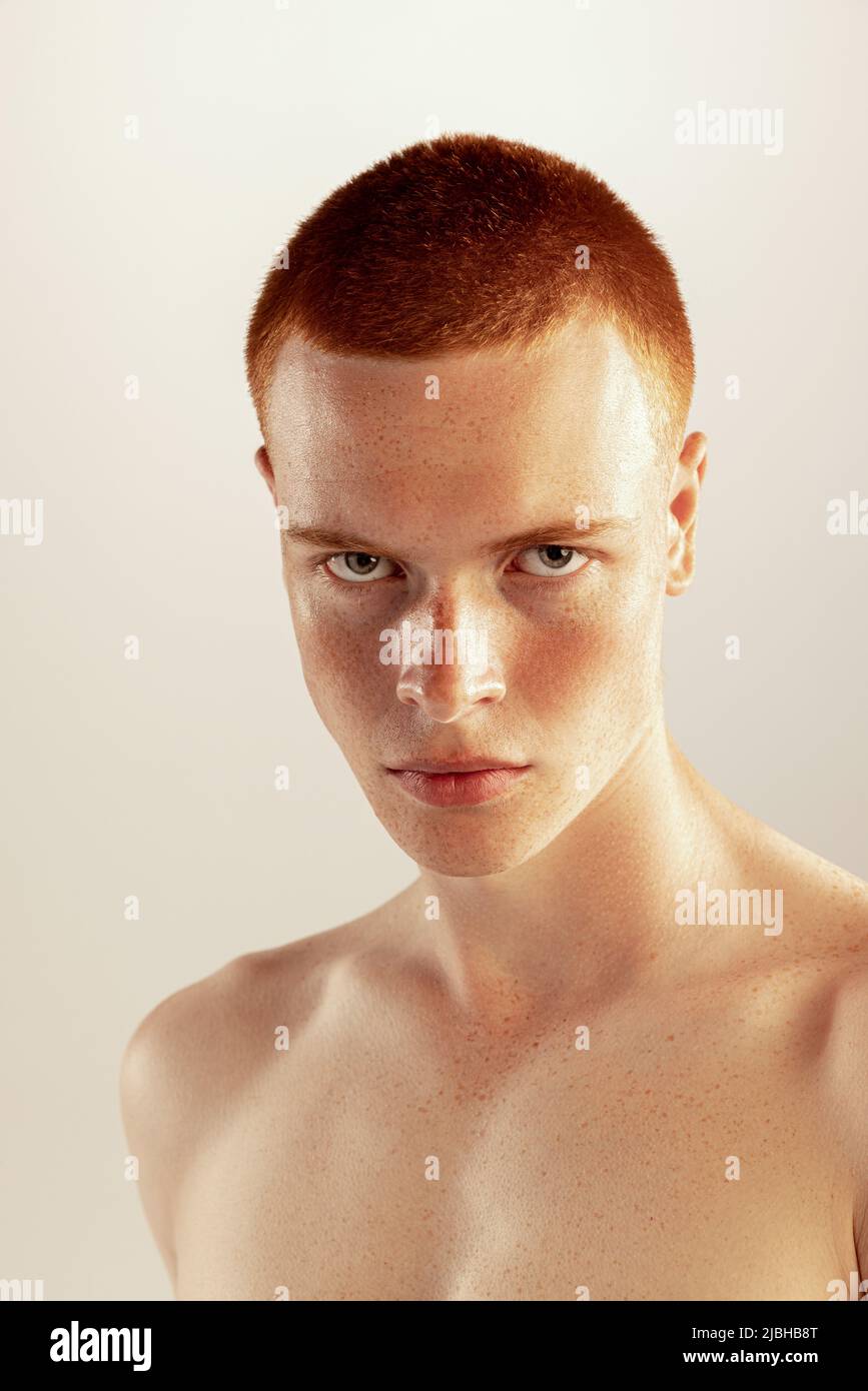 Portrait of young red-haired man with freckled face posing, seriously ...