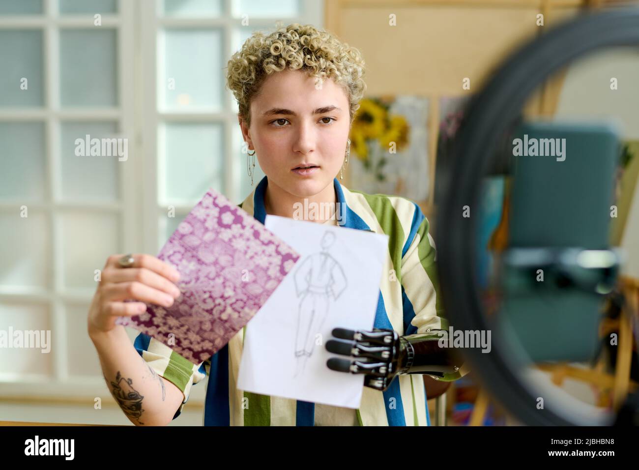 Young creative female fashion designer showing drawing of new model for ...