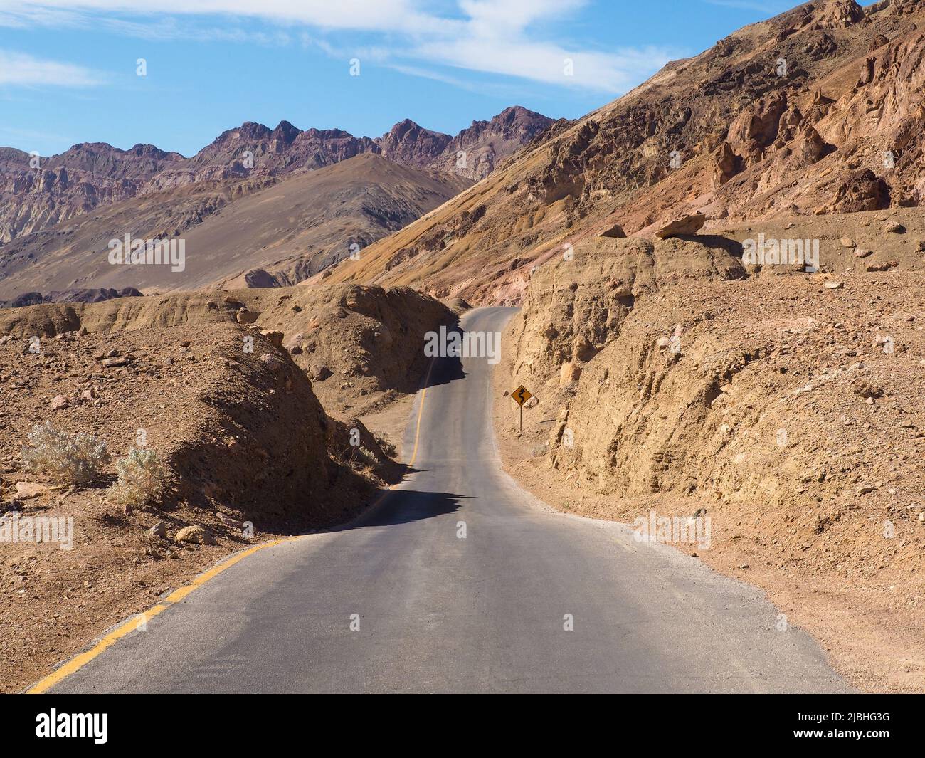 Asphalt road leading through steaming hot landscape of Death Valley ...