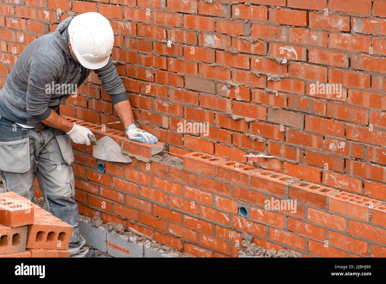 Bricklayer laying bricks on mortar on new residential house ...