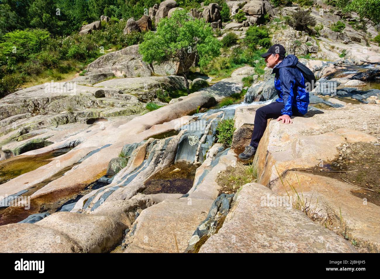 Rocky landscape with waterfalls and man sitting on a rock resting Stock ...