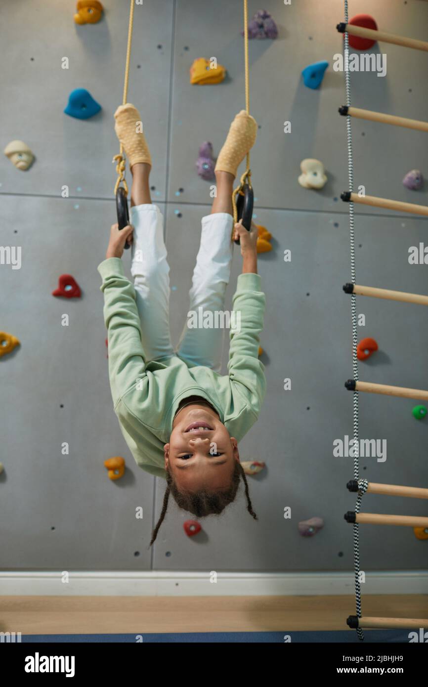 Full length portrait of active black child hanging upside down on ...