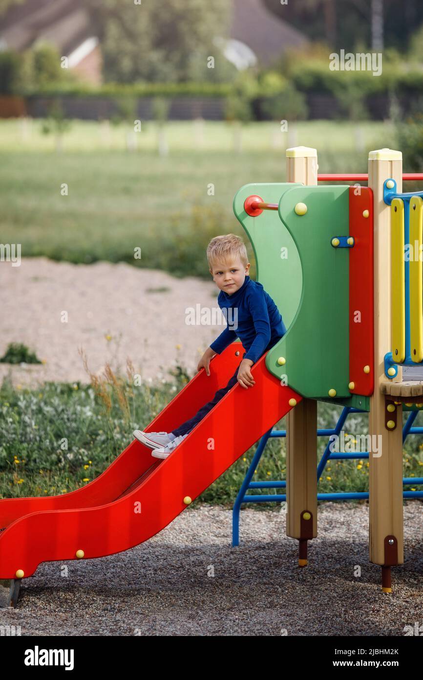The cute kid slides on the colorful modern outdoor playground slide ...