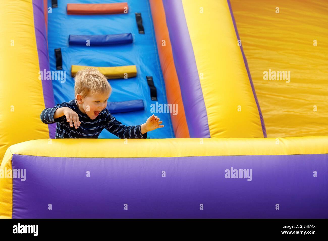 Little boy having fun on inflatable obstacle course. Joyful child ...
