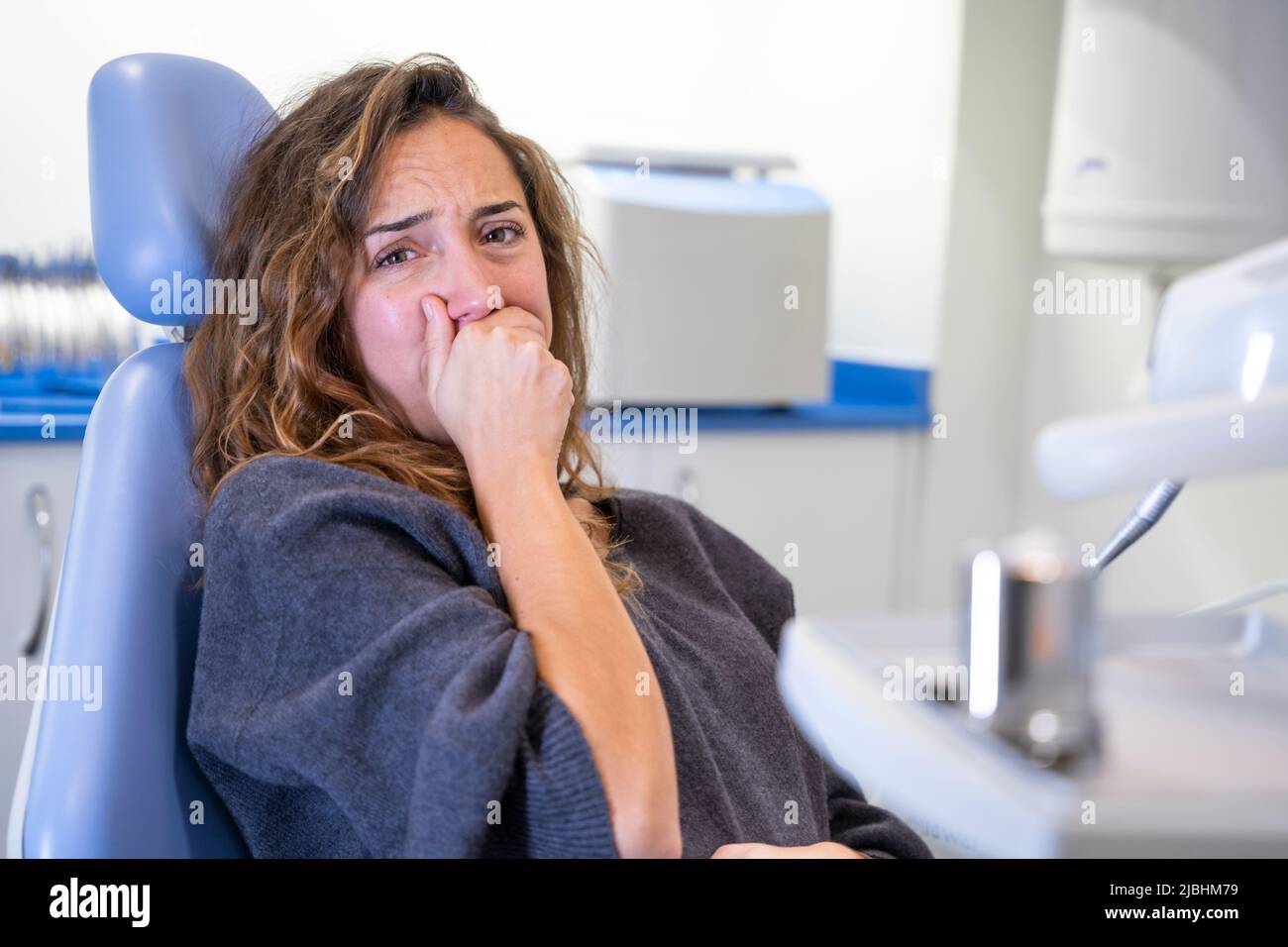 Young female patient in pain covering her mouth at the dental clinic ...