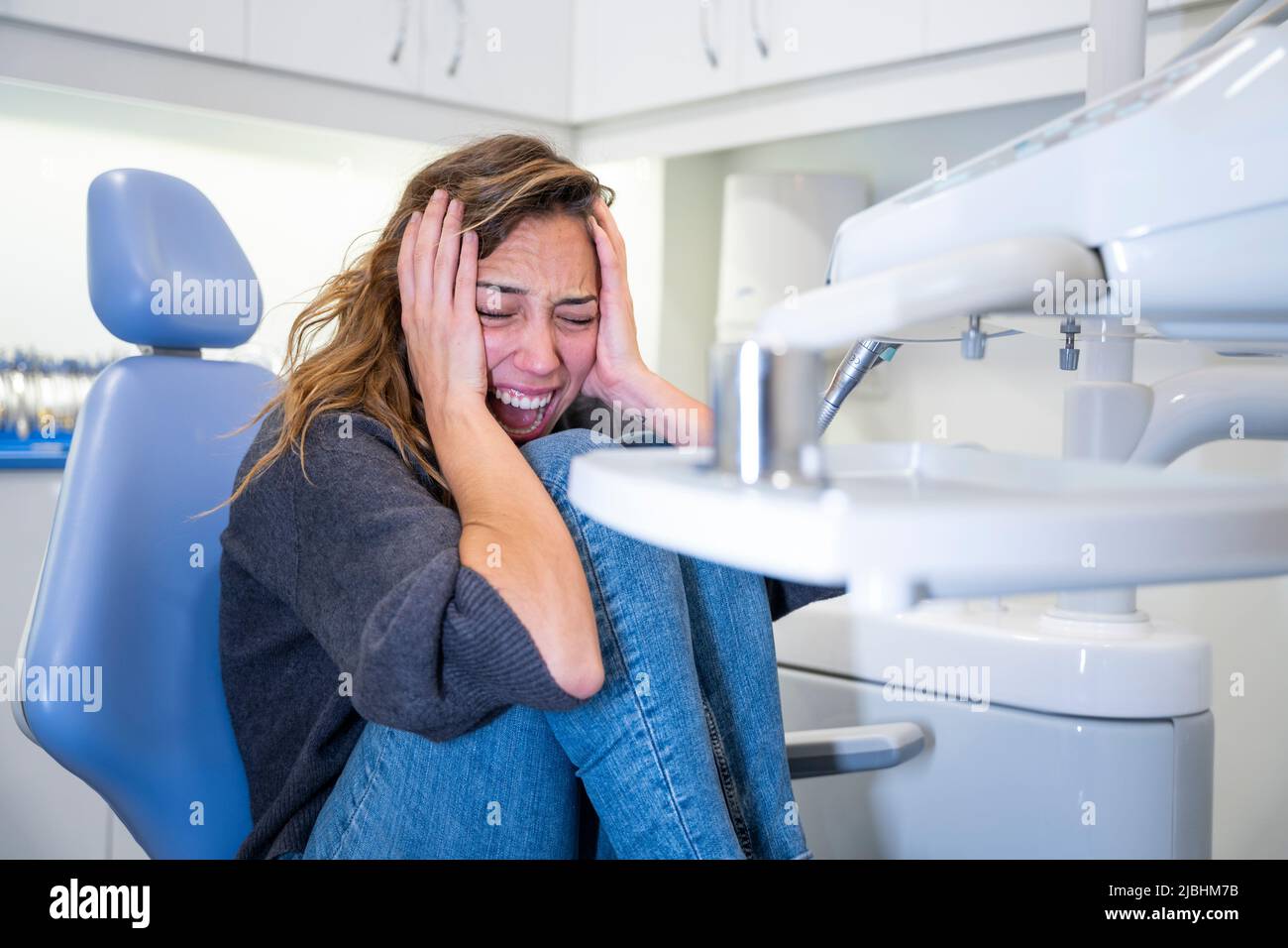 Young female patient screaming curled with the hands on her head at the ...