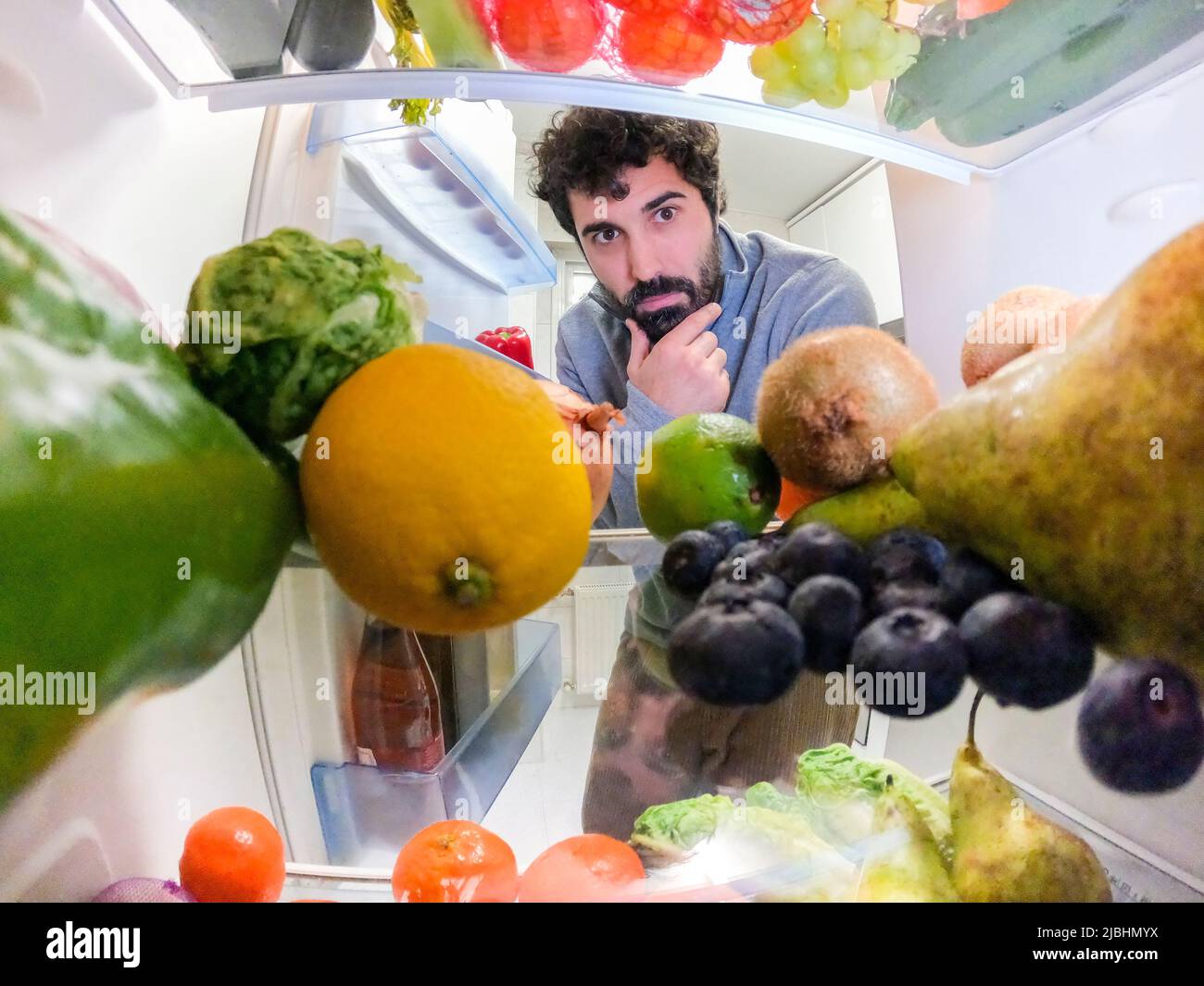 Young caucasian man thinking about which fruits and vegetables to ...