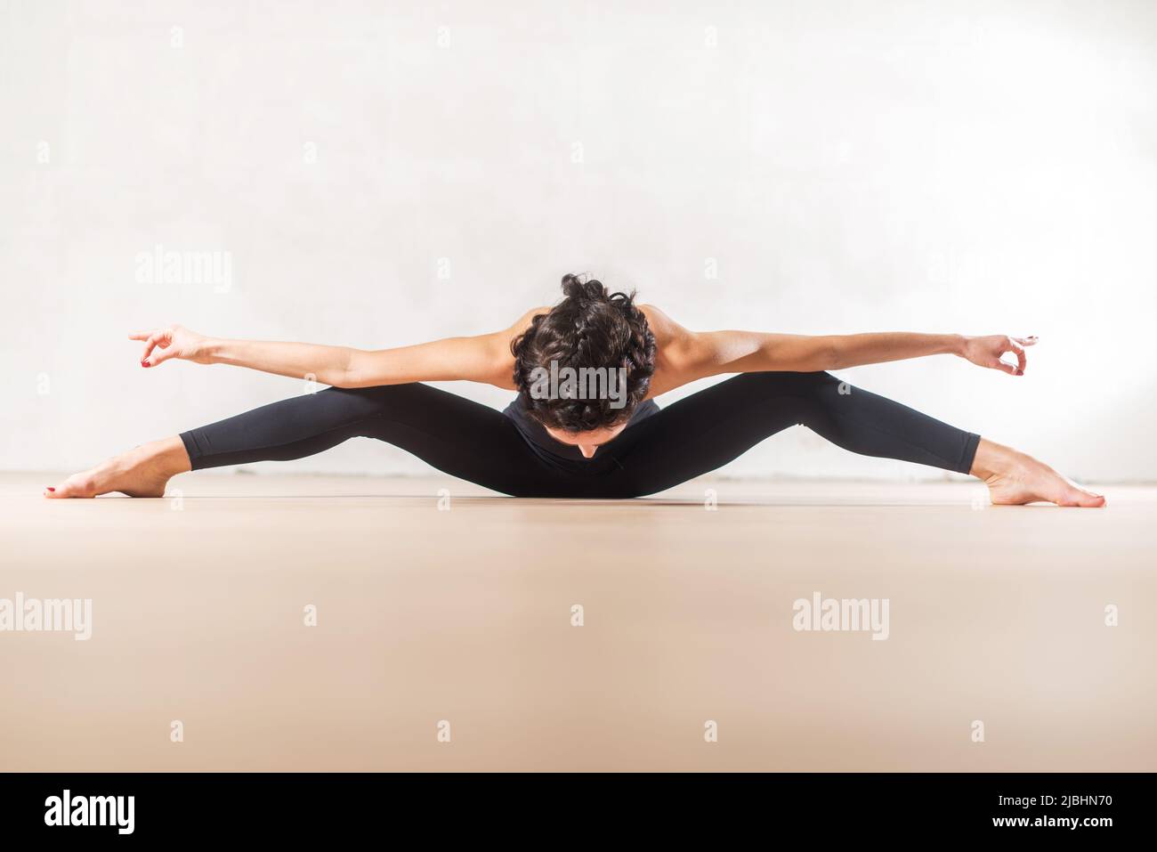 Young Caucasian dancer doing seated wide leg forward bend exercise ...