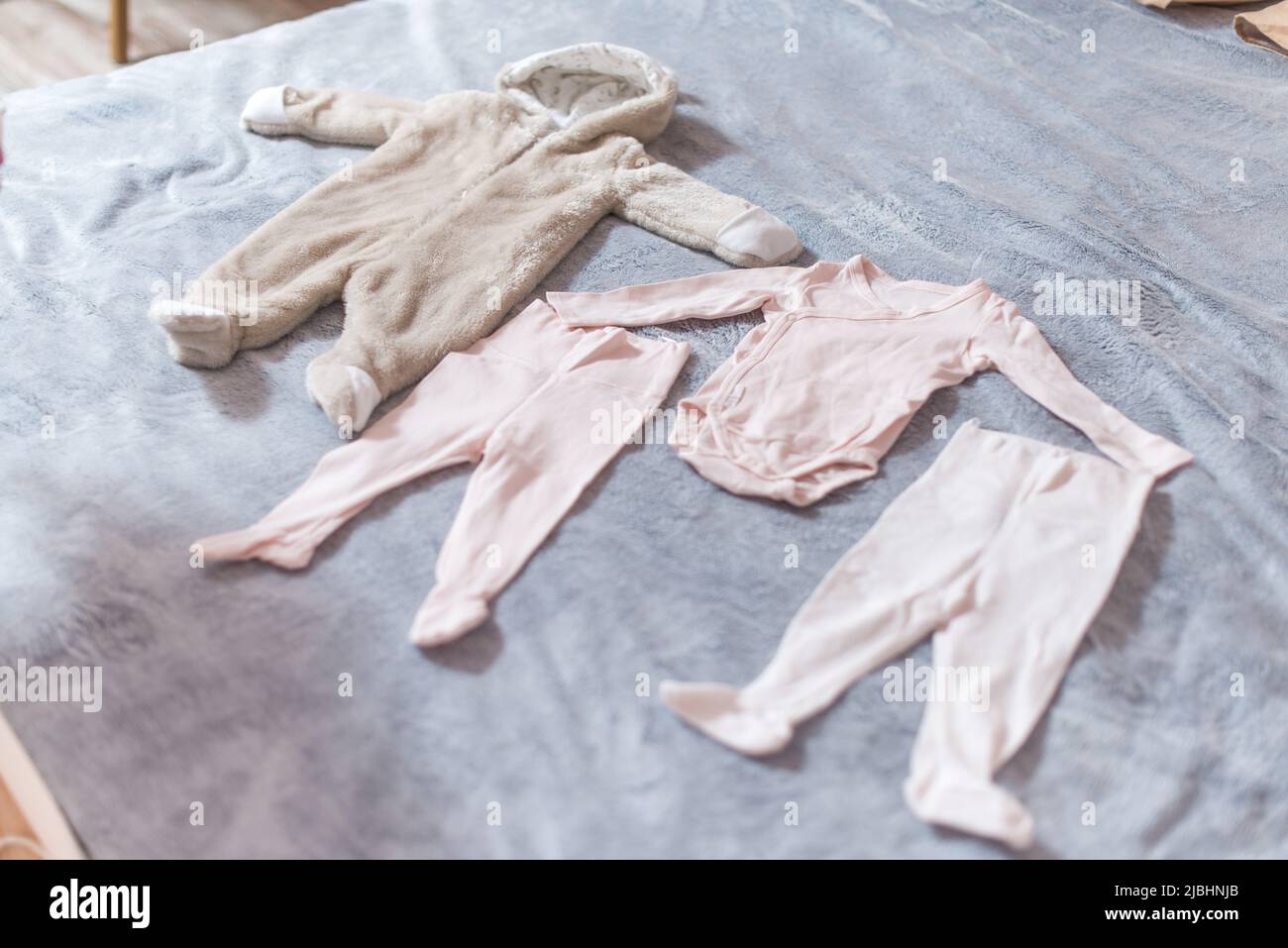 Baby's clothes laid out on bed, natural light Stock Photo - Alamy