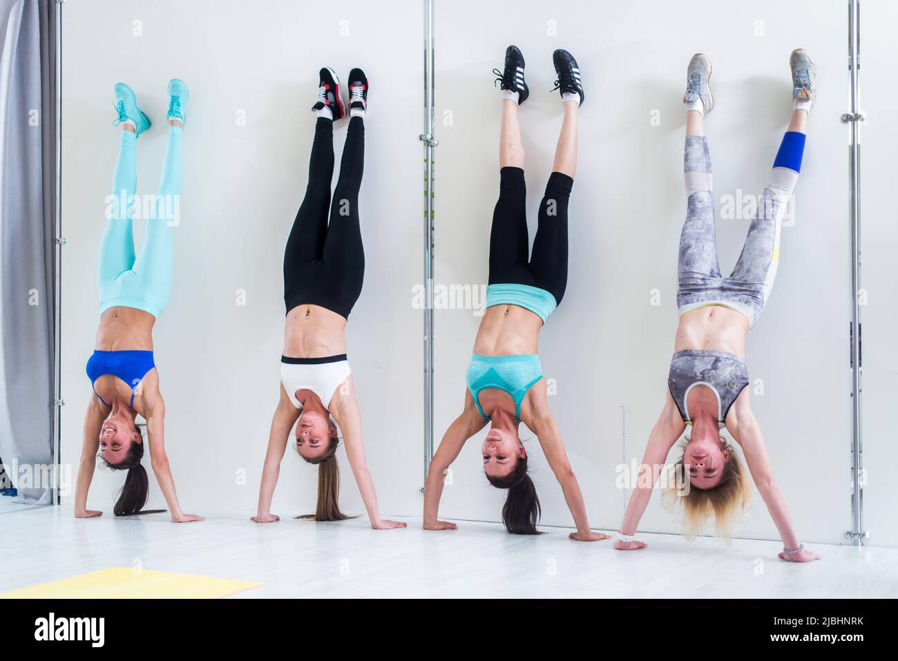 Fit girls doing handstand against wall indoors Stock Photo - Alamy