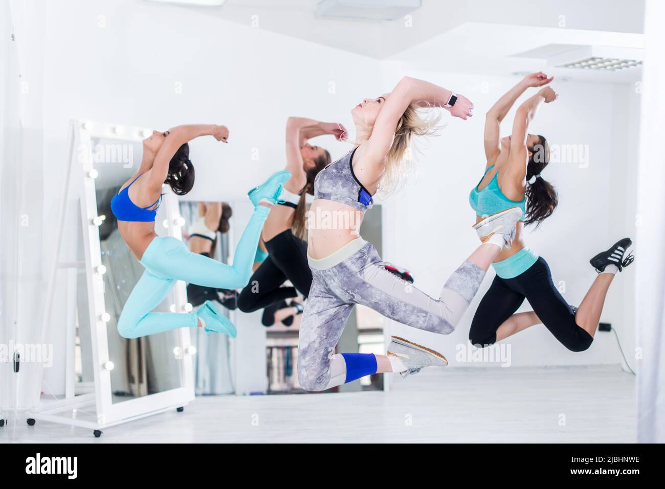 A group of slim fit athletic young women doing simultaneous jump in ...
