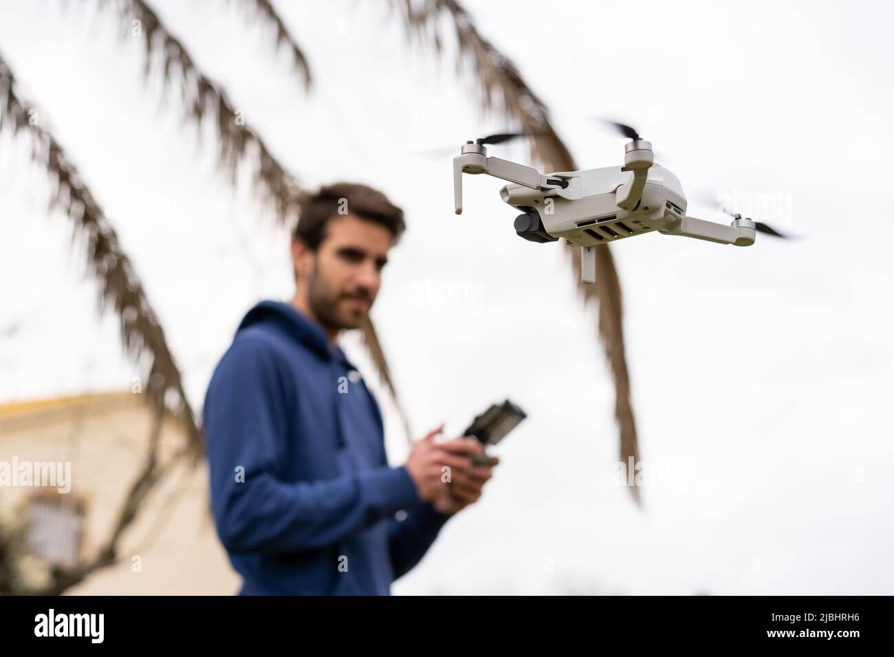 Young man with remote control operating flying drone outdoors with ...