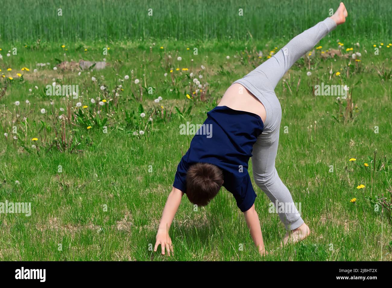 Boy makes an acrobatic wheel. On the grass Stock Photo - Alamy