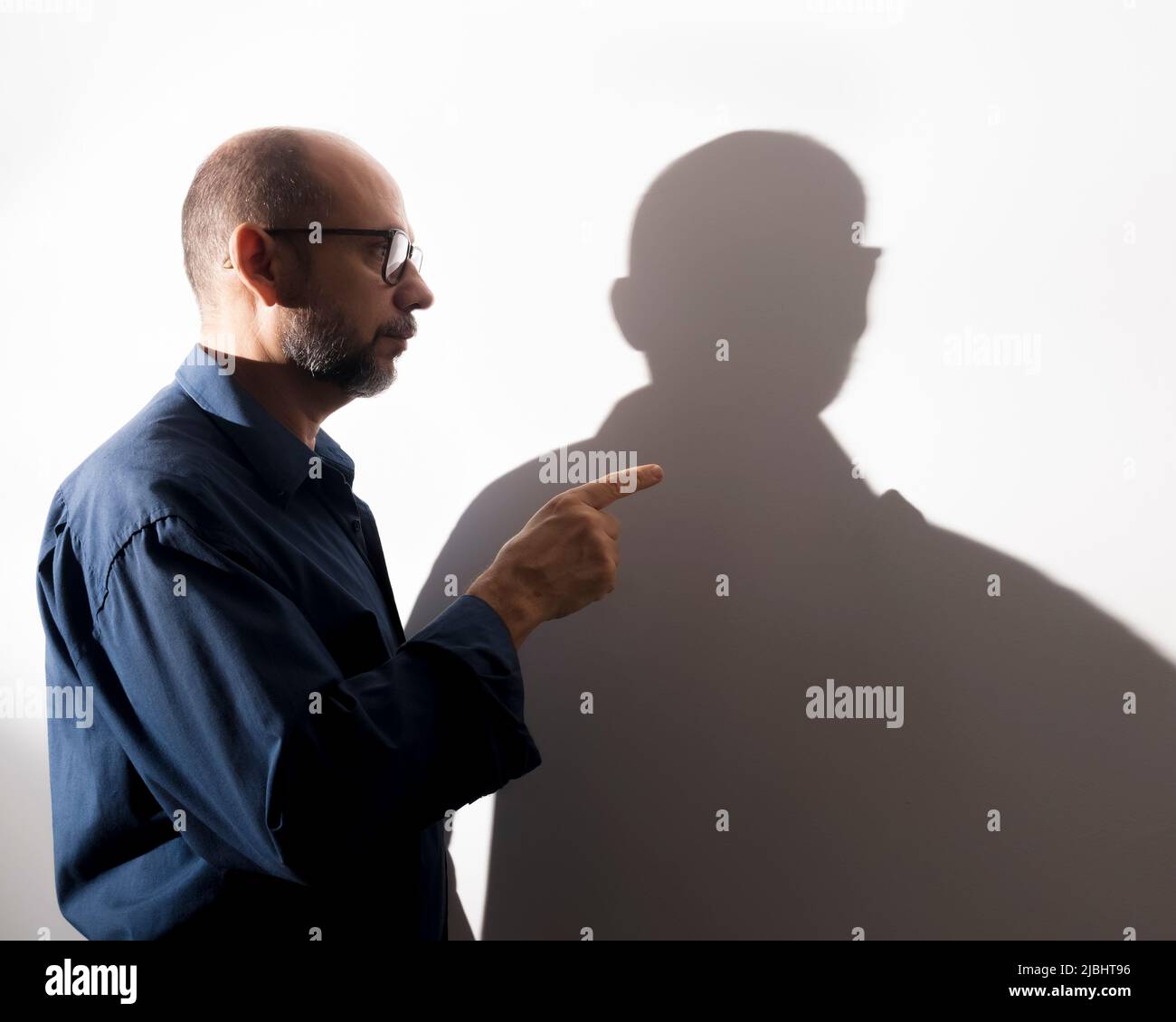 Portrait of a man and his shadow against white wall background ...