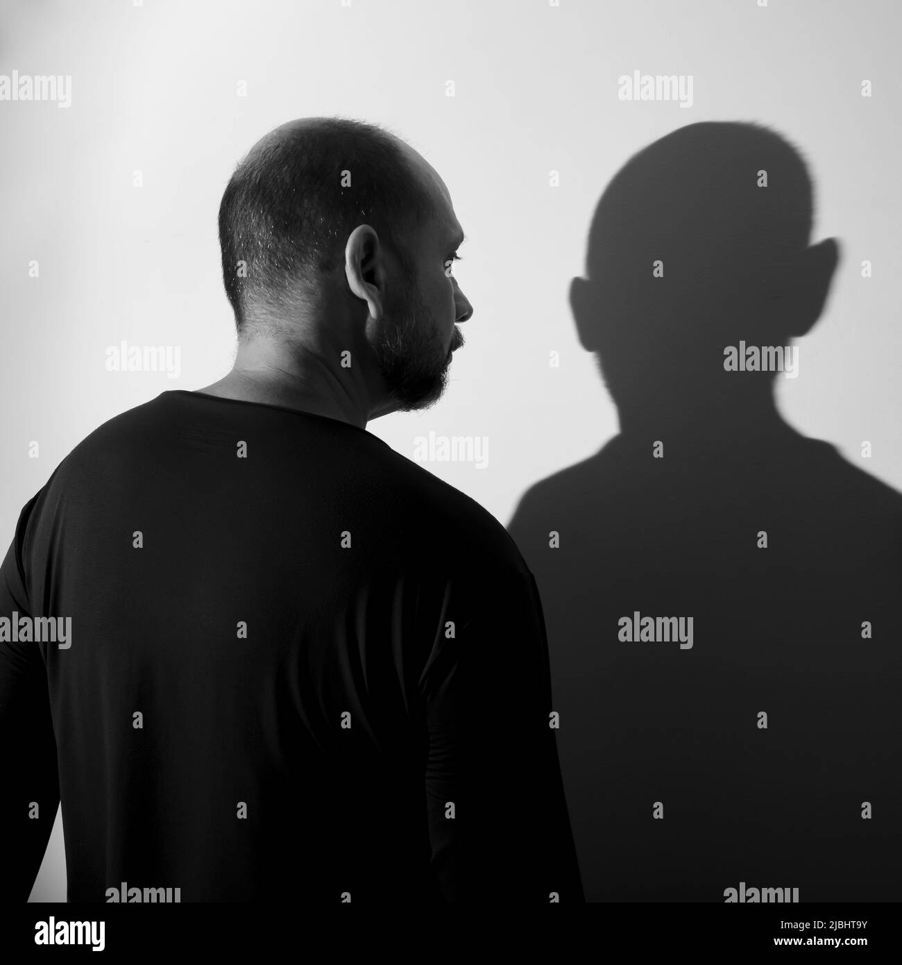 Portrait of a man and his shadow against white wall background ...