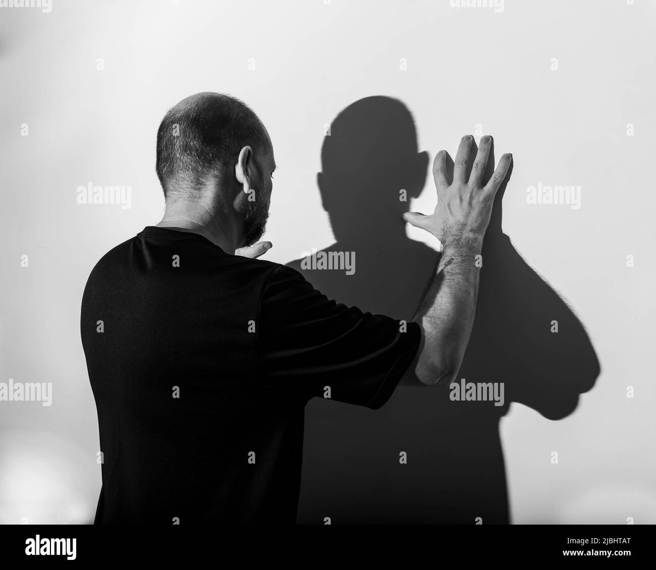Portrait of a man and his shadow against white wall background ...