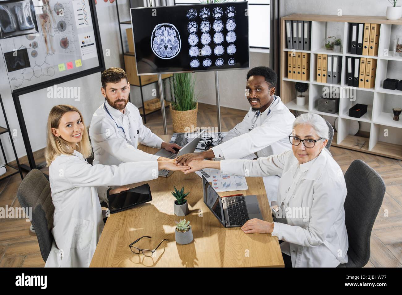 Portrait of multiracial group of happy doctors holding hands together ...