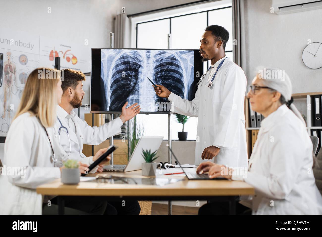Four multicultural doctors looking at digital screen with x-ray of ...