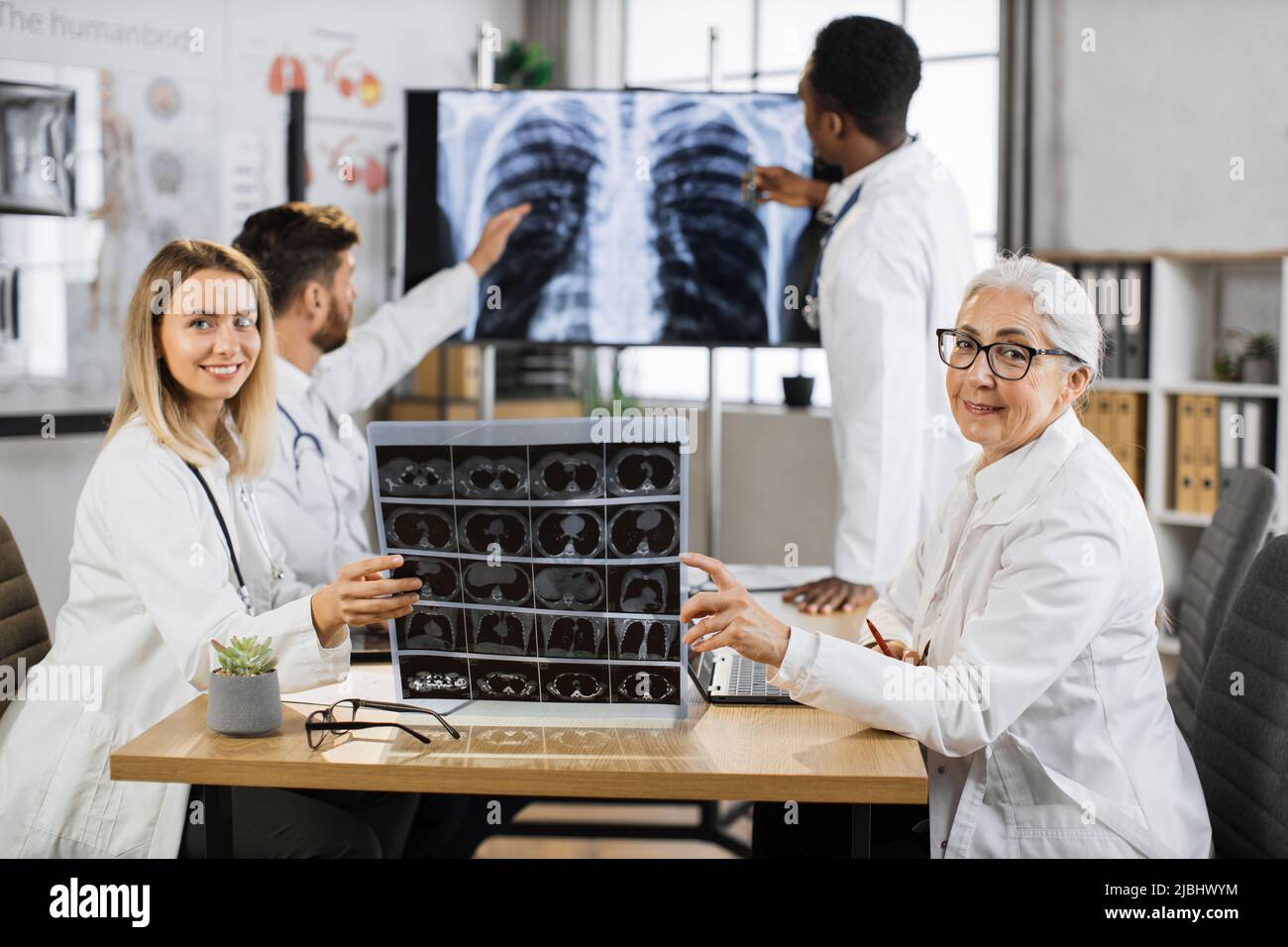 Competent female therapists smiling and looking at camera with x ray ...