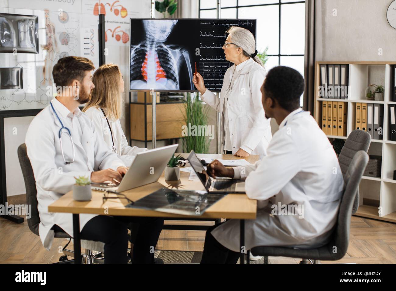 Aged medical worker discussing with multiracial colleagues x ray scan ...