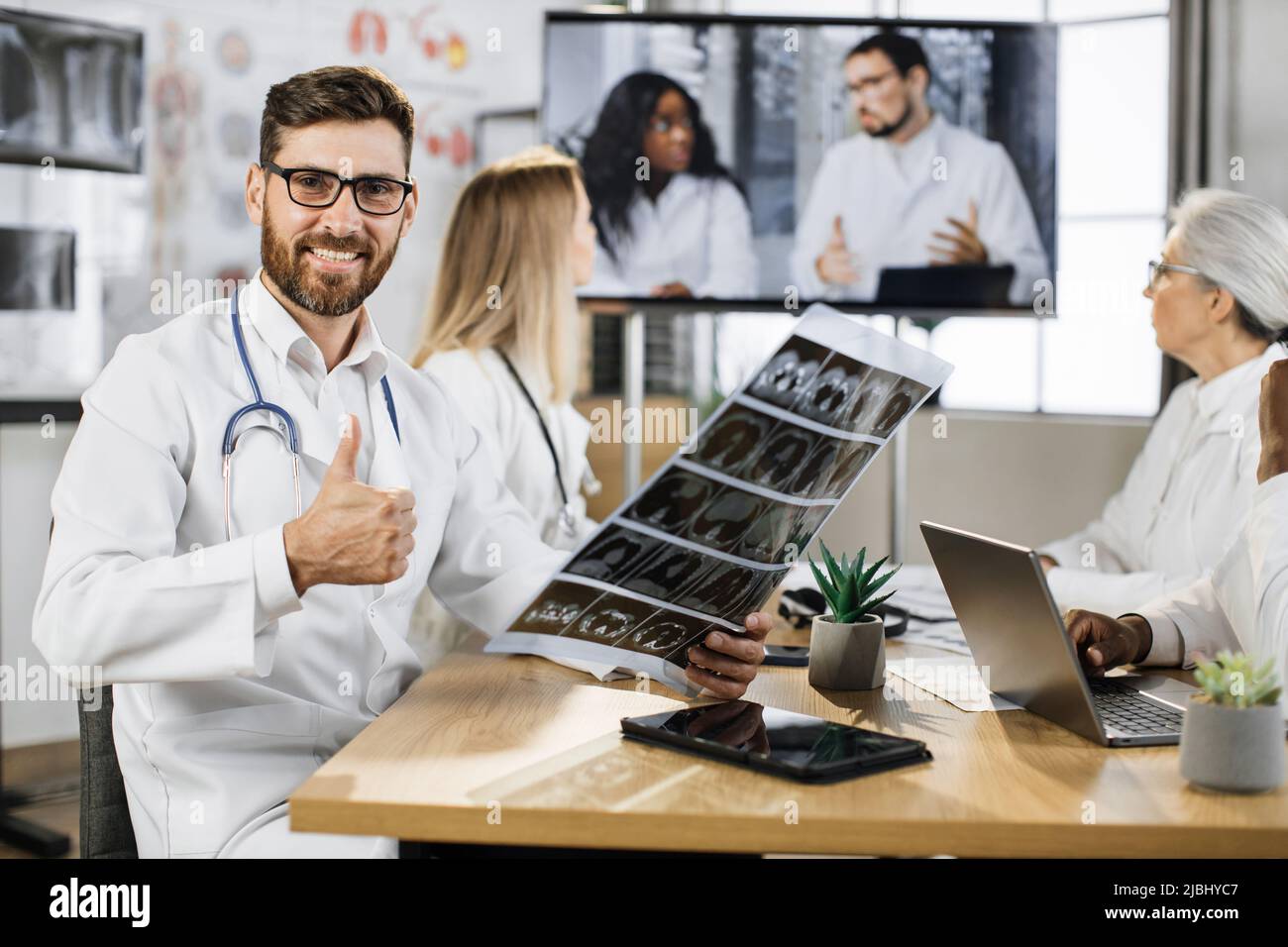 Male orthopedist holding patient x ray result and looking at camera ...
