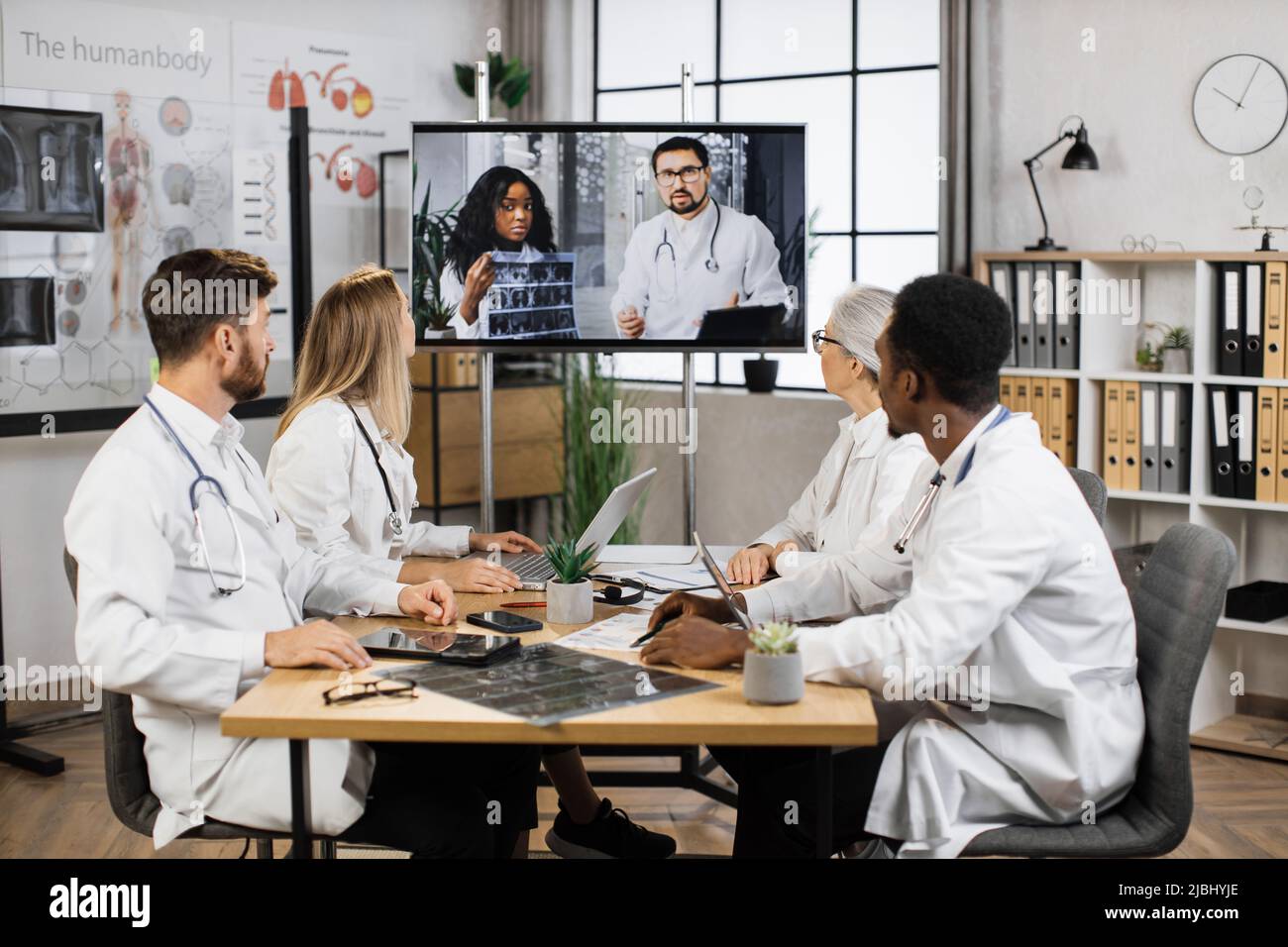 Group of four multicultural physicians watching online lecture about ...