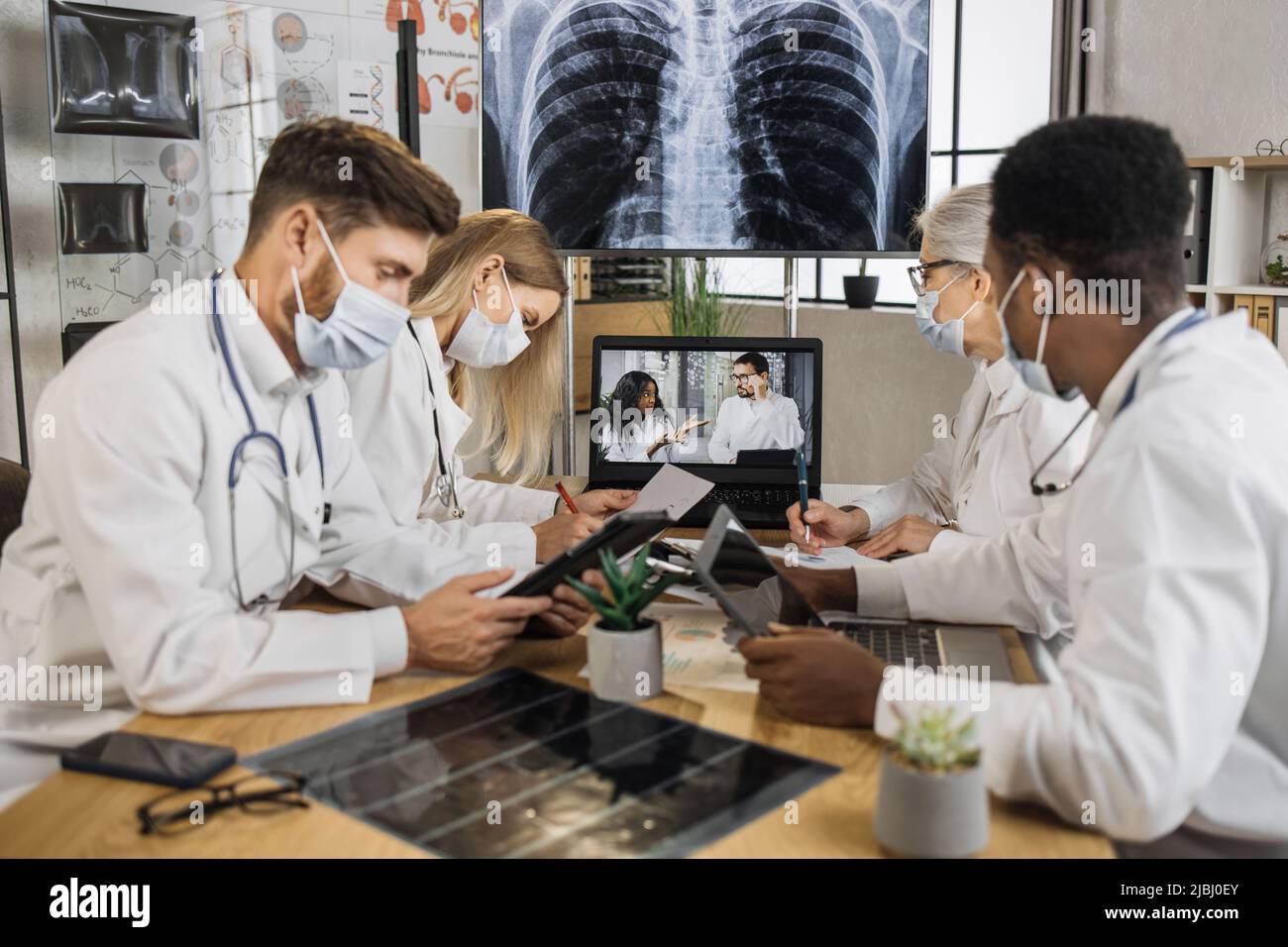 Group of multicultural medics in masks having video conference on ...