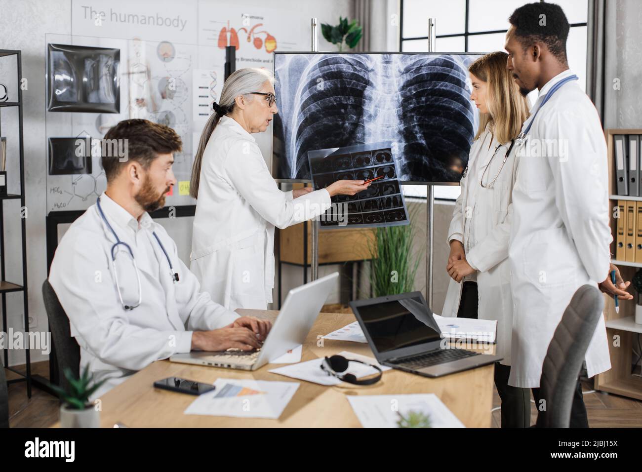 Senior female medical specialist holding x ray scan and explaining ...