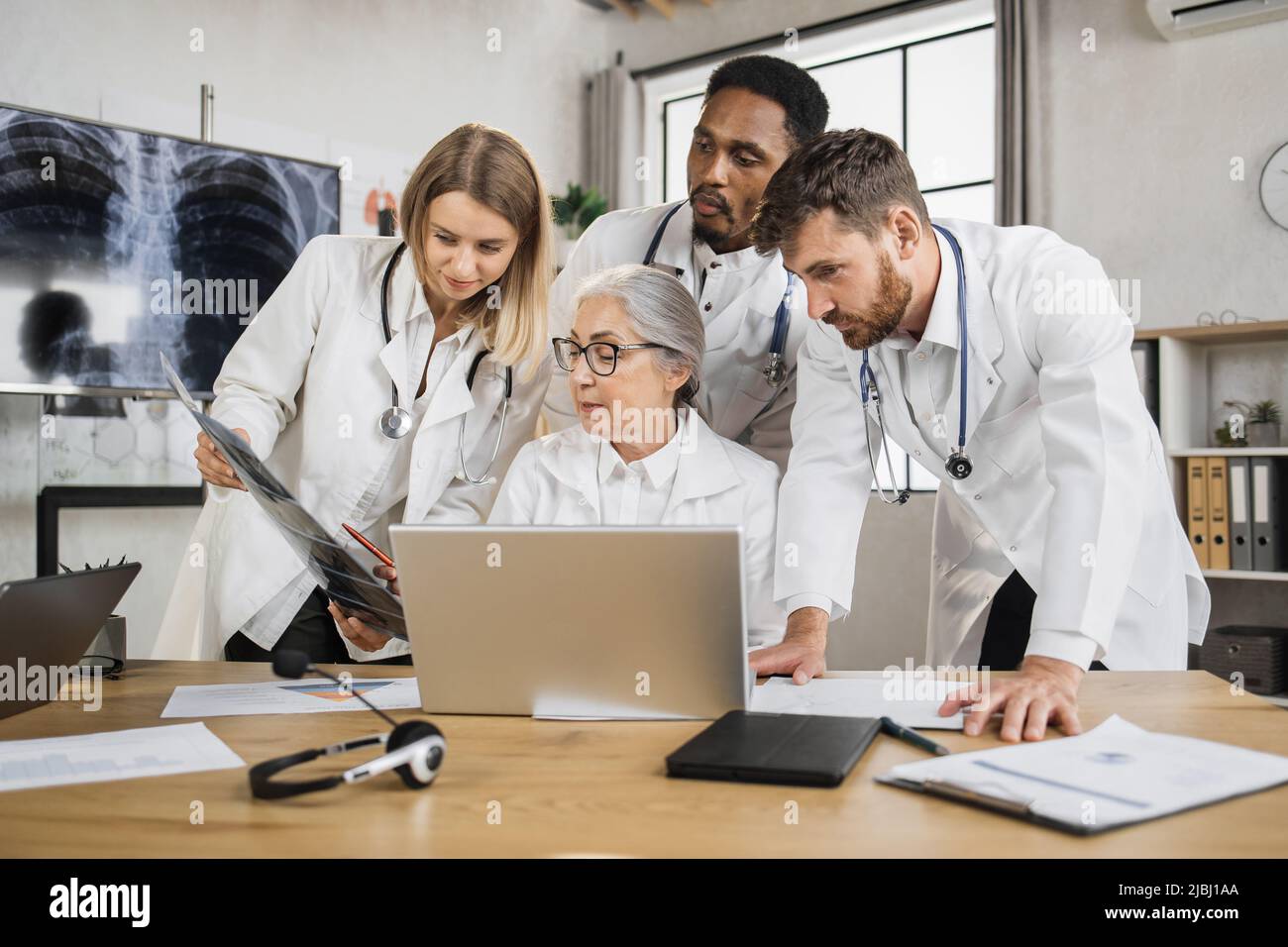 Multiethnic physicians discussing x ray scan while standing around ...