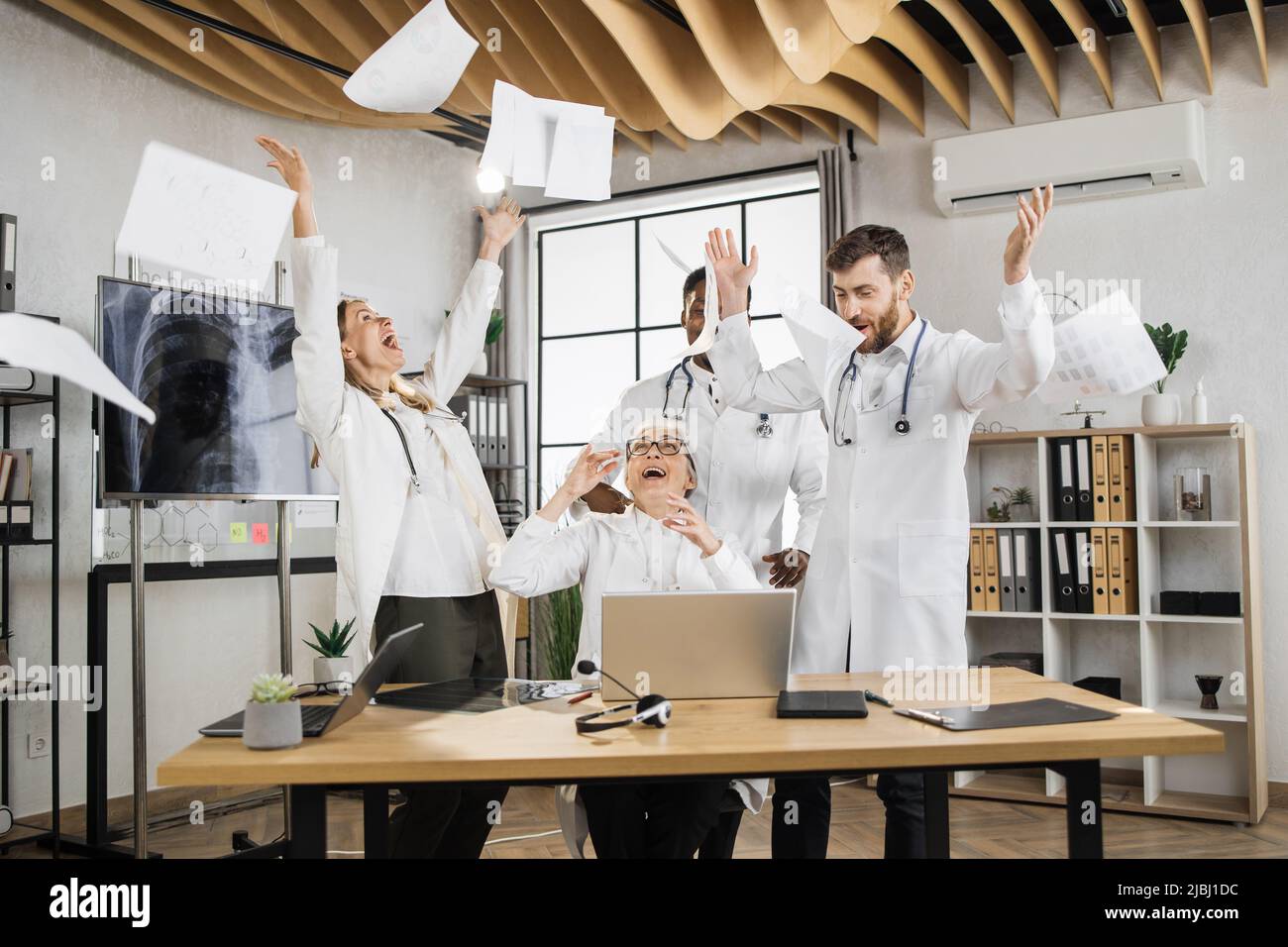 Excited multiracial scientists in white medical uniform laughing and ...