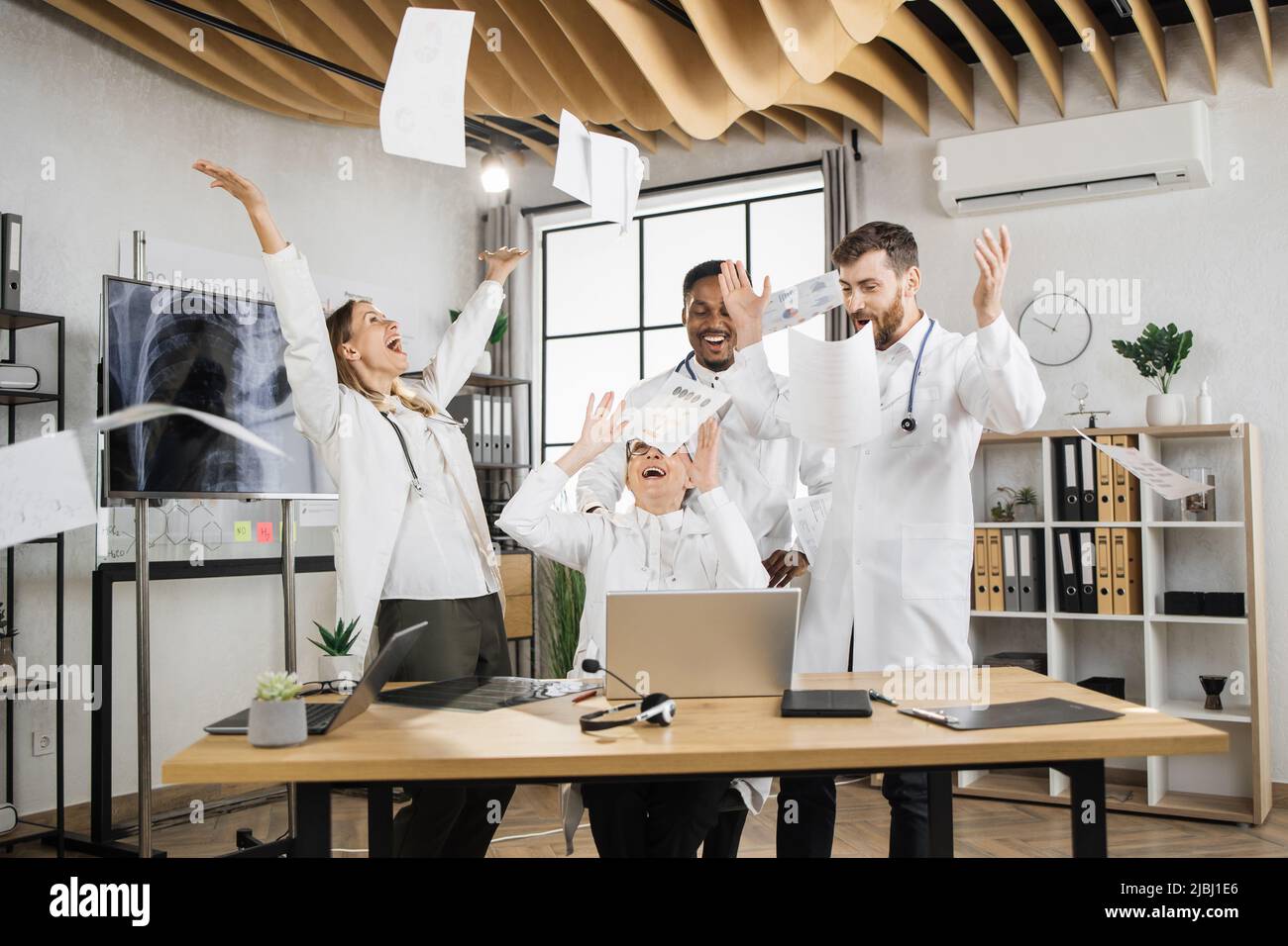 Excited multiracial scientists in white medical uniform laughing and ...