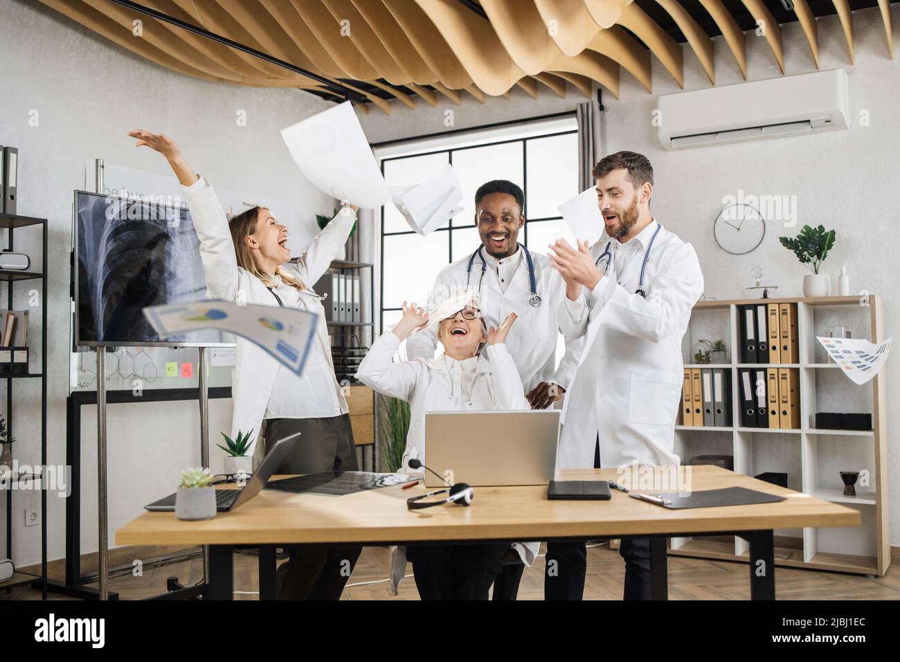 Excited multiracial scientists in white medical uniform laughing and ...