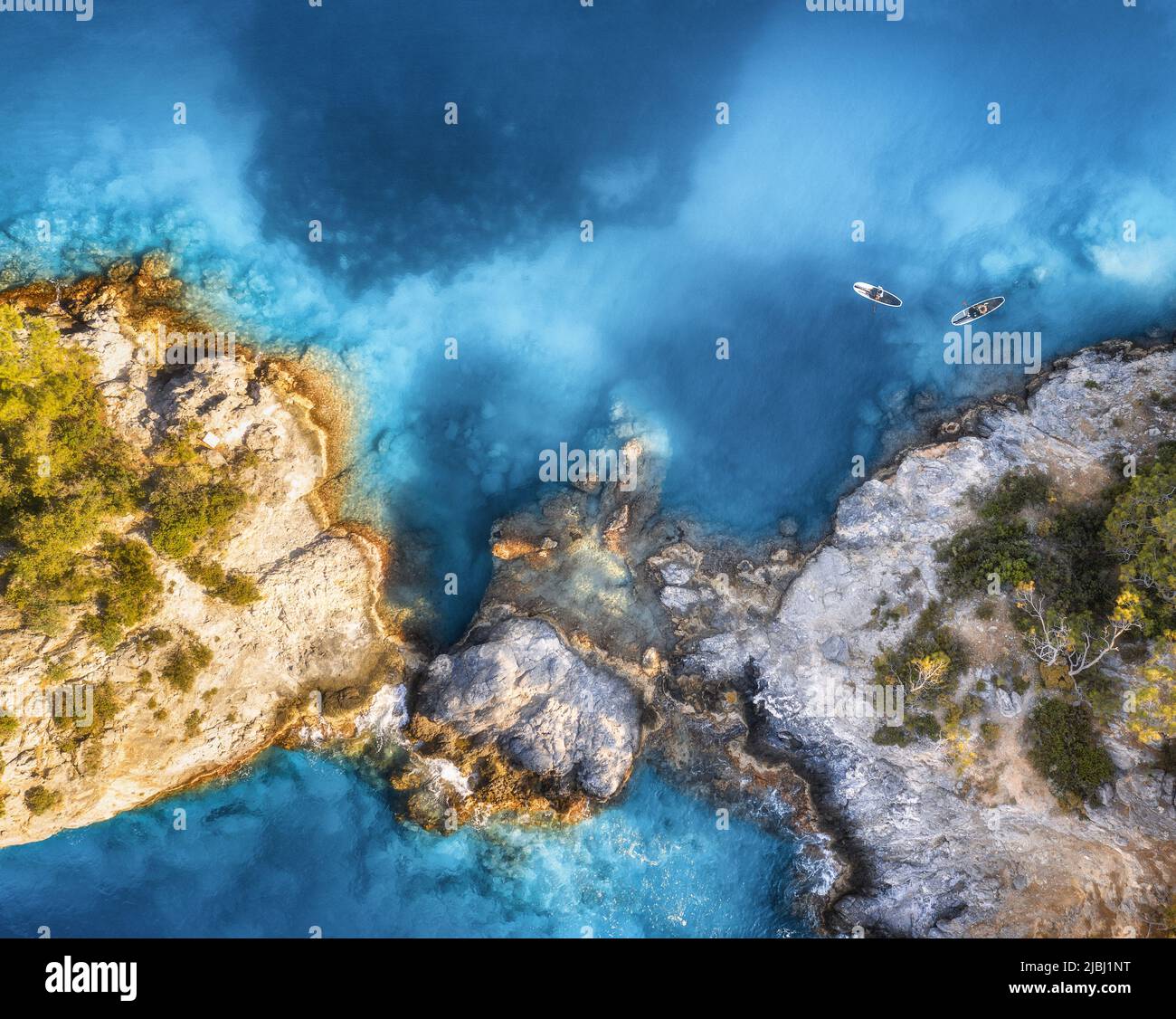 Aerial view of people on floating sup boards on blue sea, rocks Stock ...
