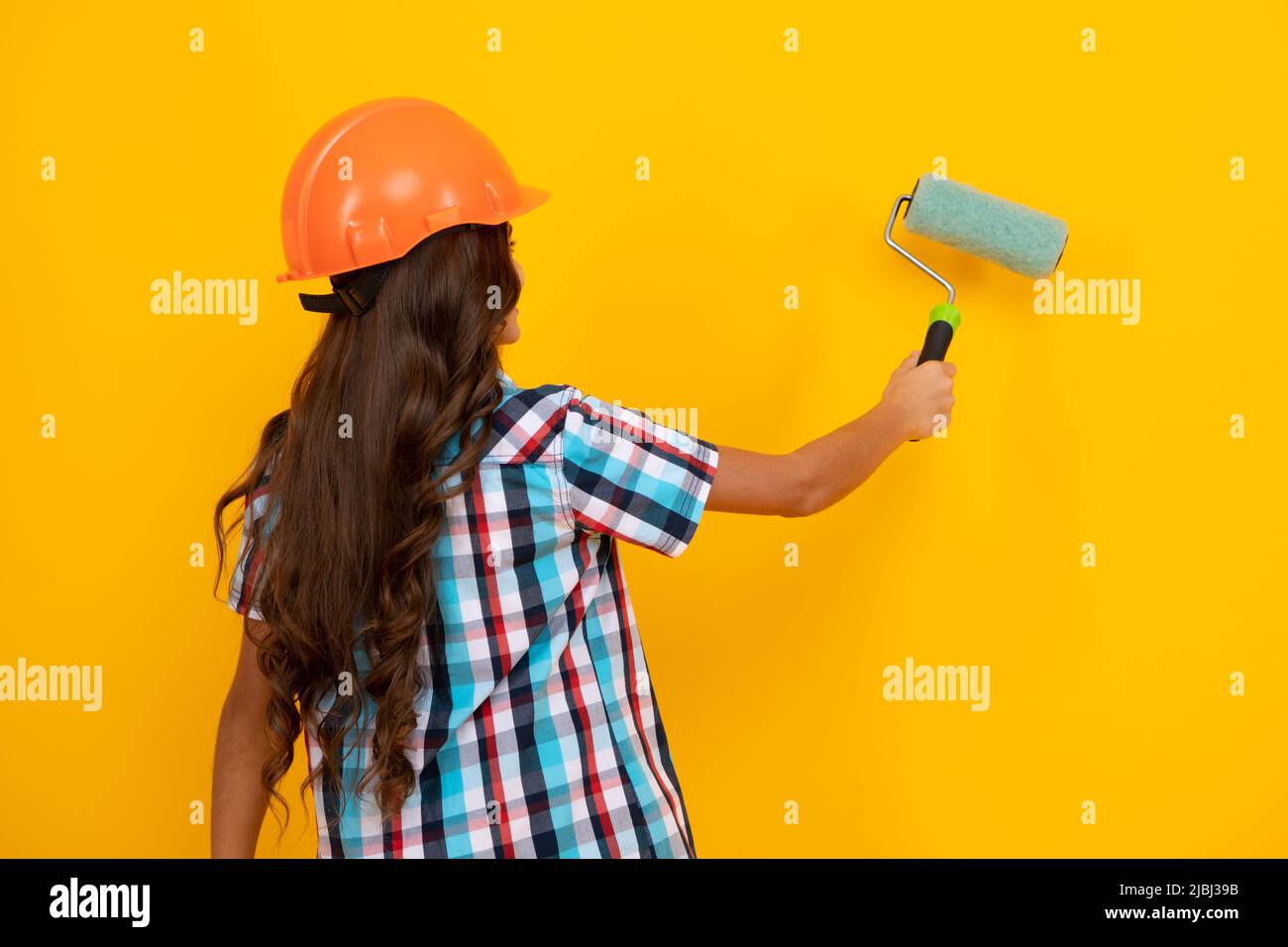 Little builder expert in helmet on construction site. Teen girl painter ...
