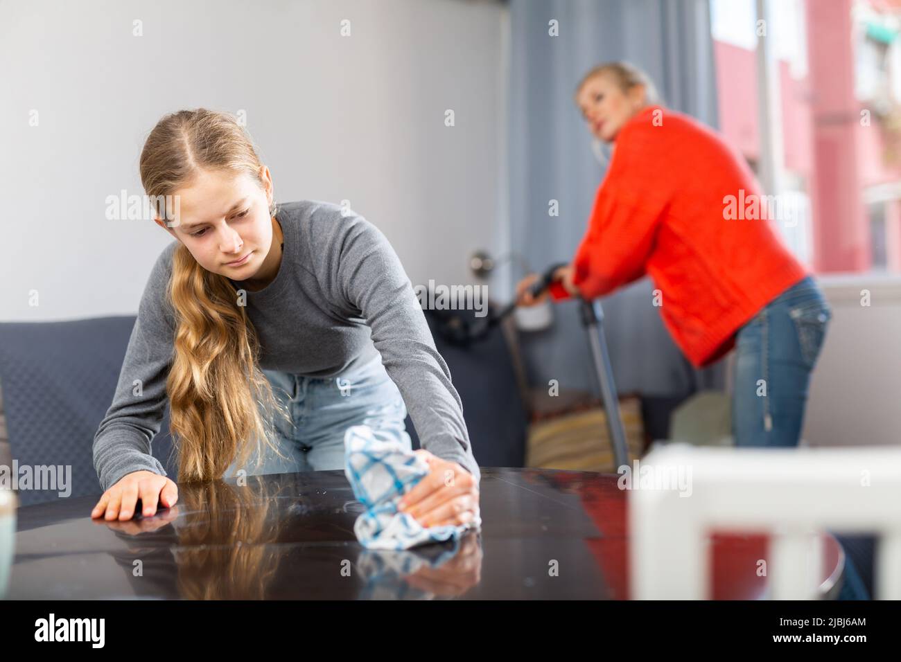 Teenage girl cleaning table with rag Stock Photo - Alamy