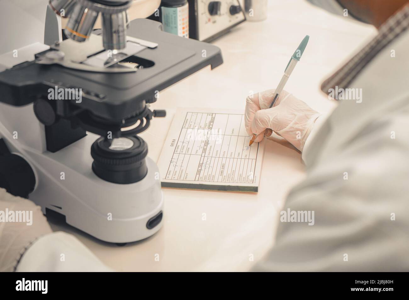 Clinical analyst writing down the results of a laboratory sample ...