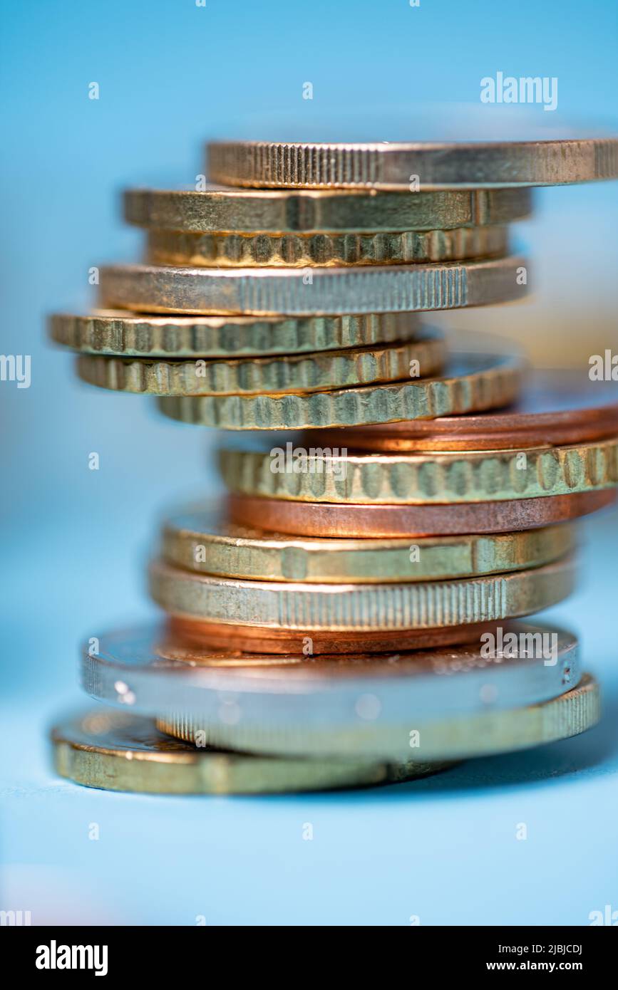 Euro coins piled up to a tower, closeup of euro currency. Blue ...