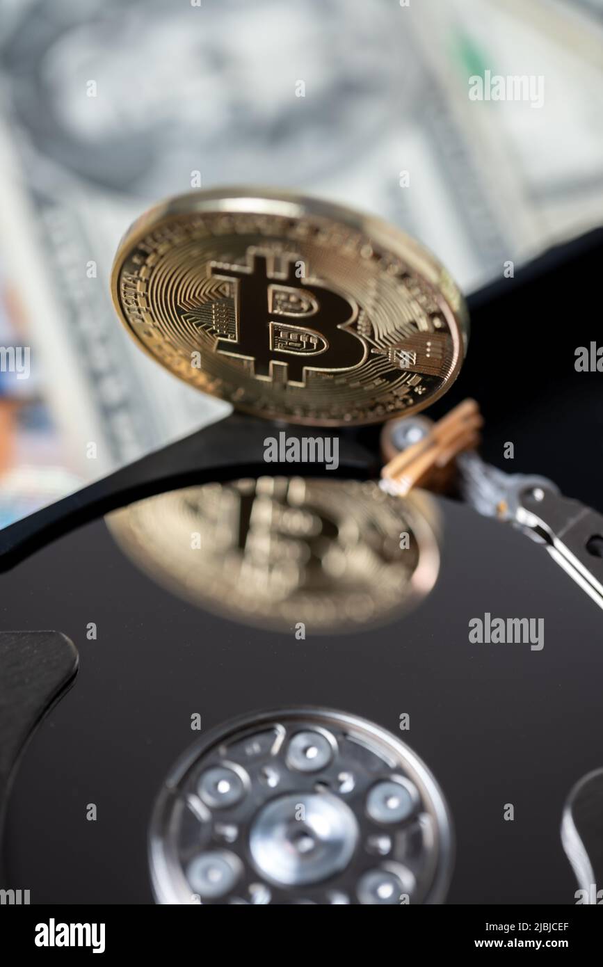 Bitcoin reflecting on hard drive platter with dollar banknotes in the ...