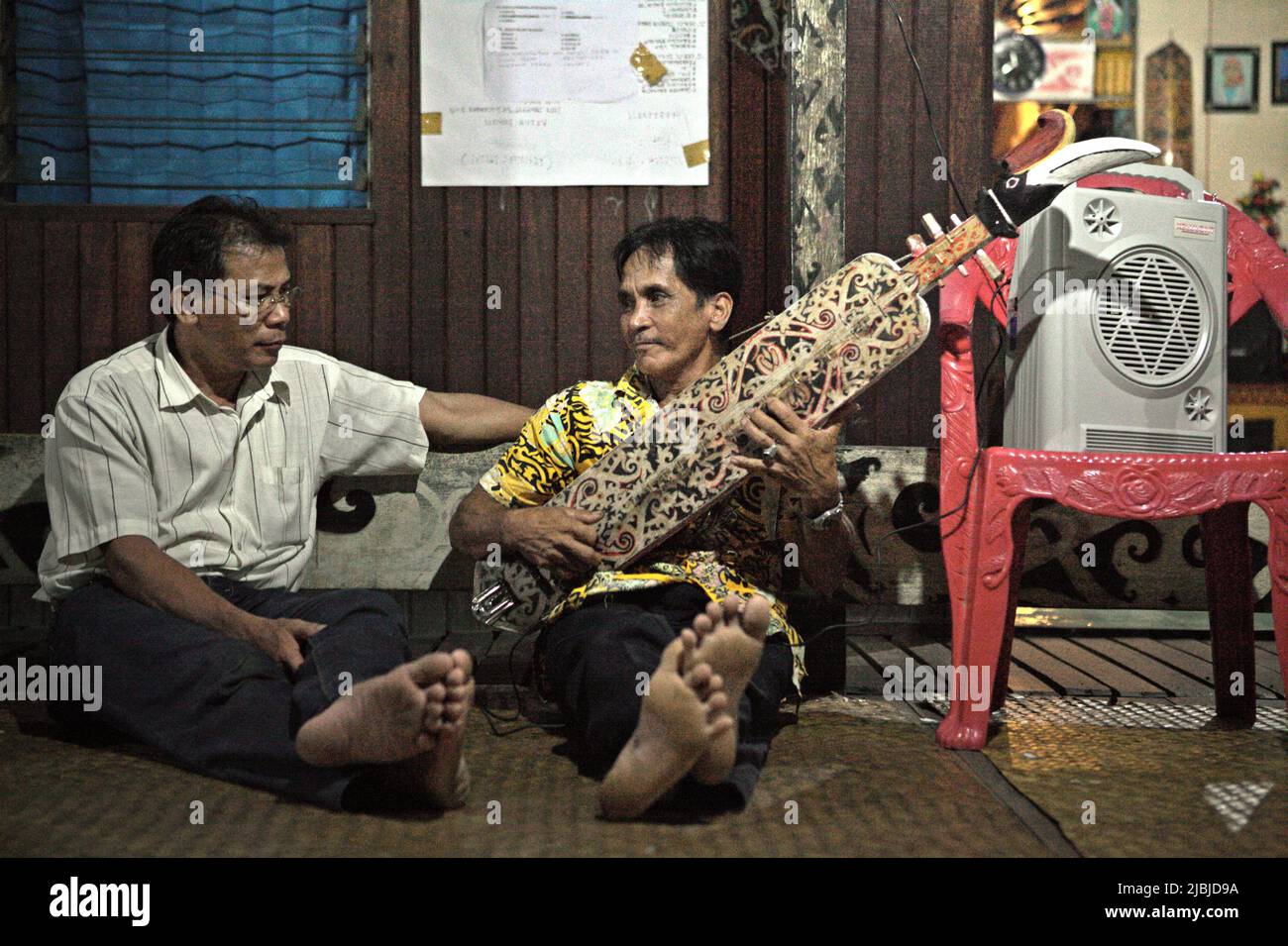 A man playing "sampe" (sape), a Dayaknese traditional string instrument ...