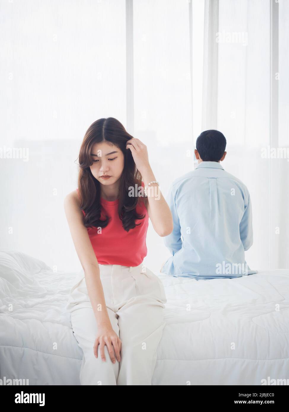 The anxiety of Asian couple lovers on the bed. Sad young woman and man ...