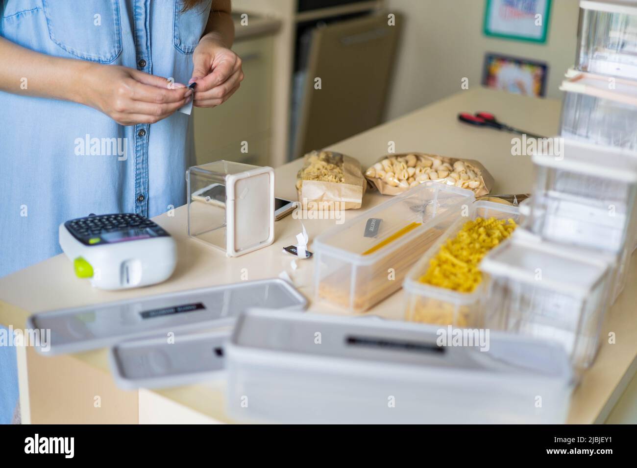 Focused female professional space organizer marking plastic case boxes ...